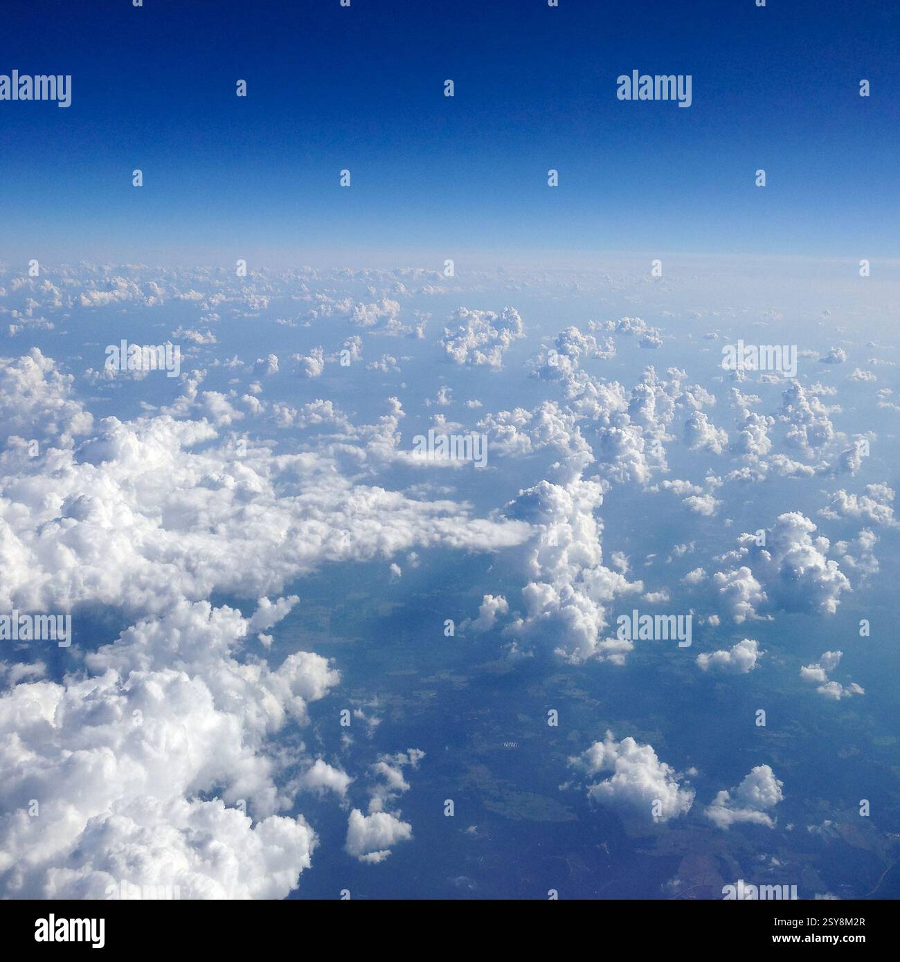 Aerial view of clouds from an airplane window with bright blue sky ...