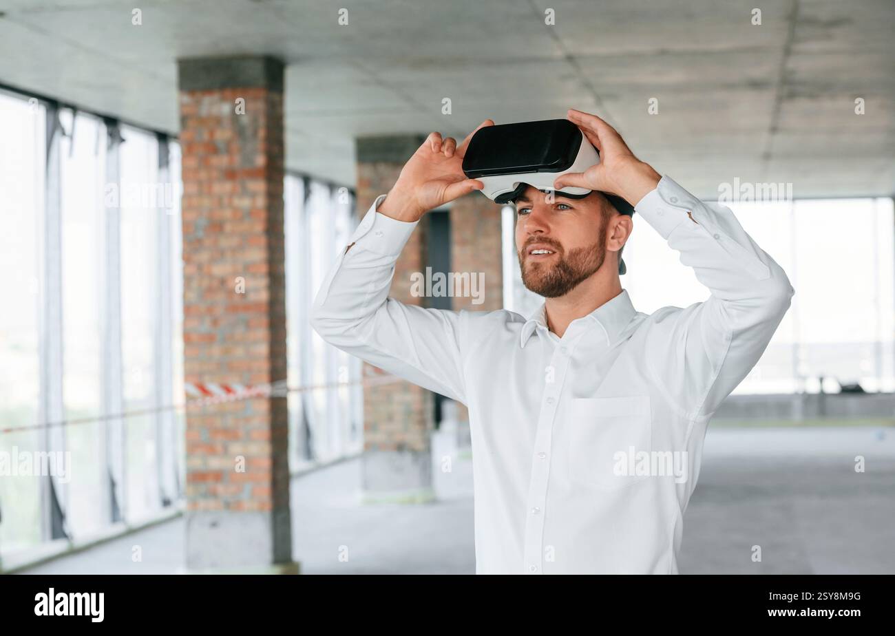 Man in formal clothes is playing VR game in the building that are on ...