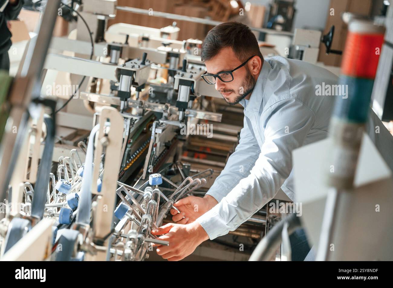 Setting up a printing machine. Typography worker in white clothes is indoors Stock Photo - Alamy