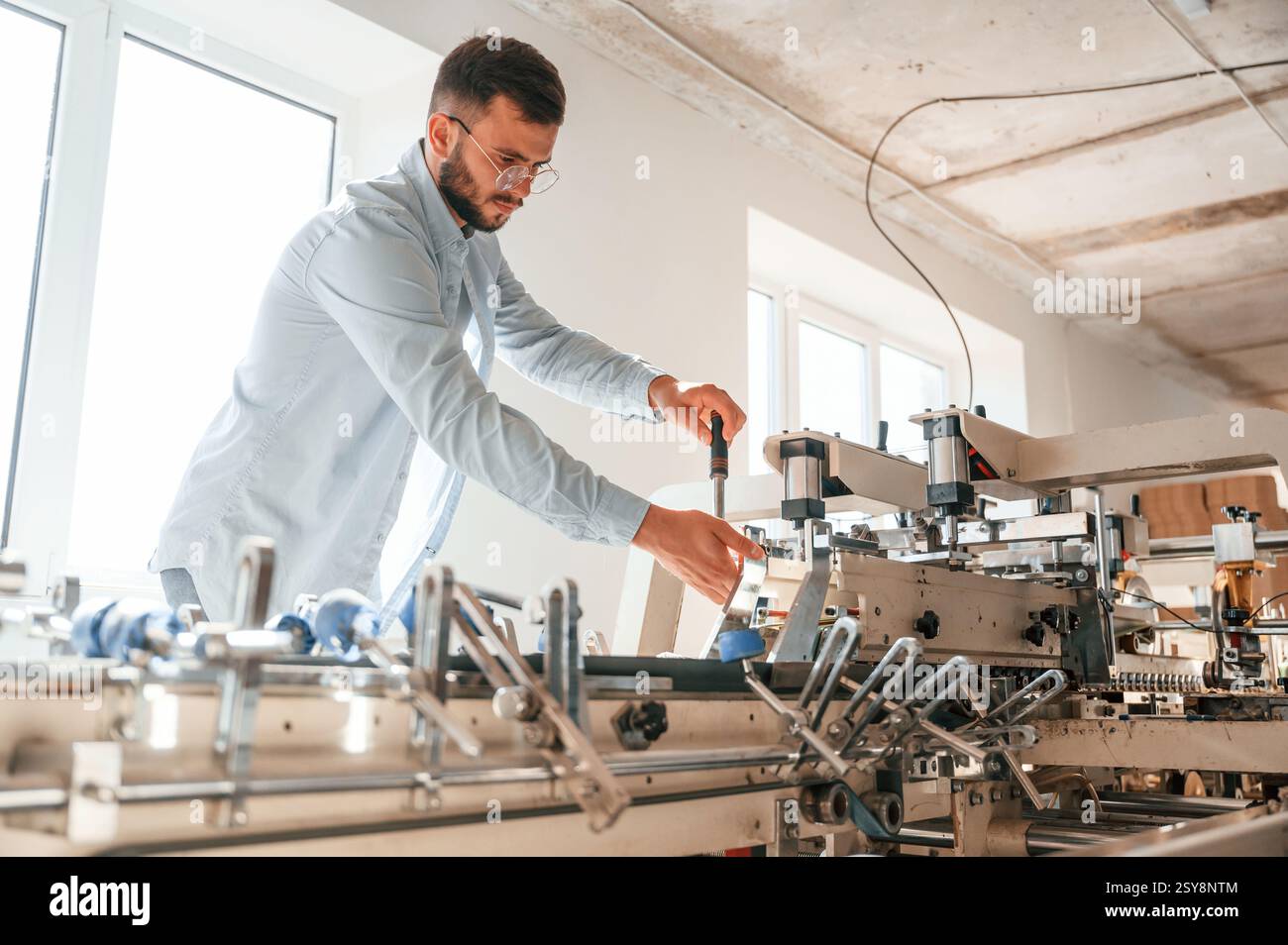 Setting up a printing machine. Typography worker in white clothes is ...