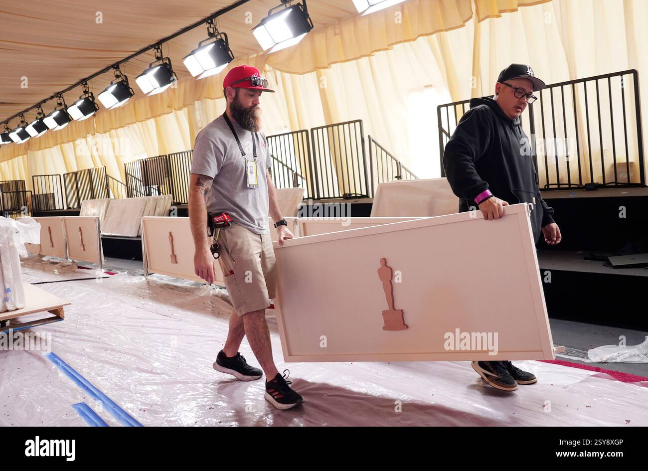Oscars crew members Greg Pena, left, and Jay Ribas carry a stanchion ...