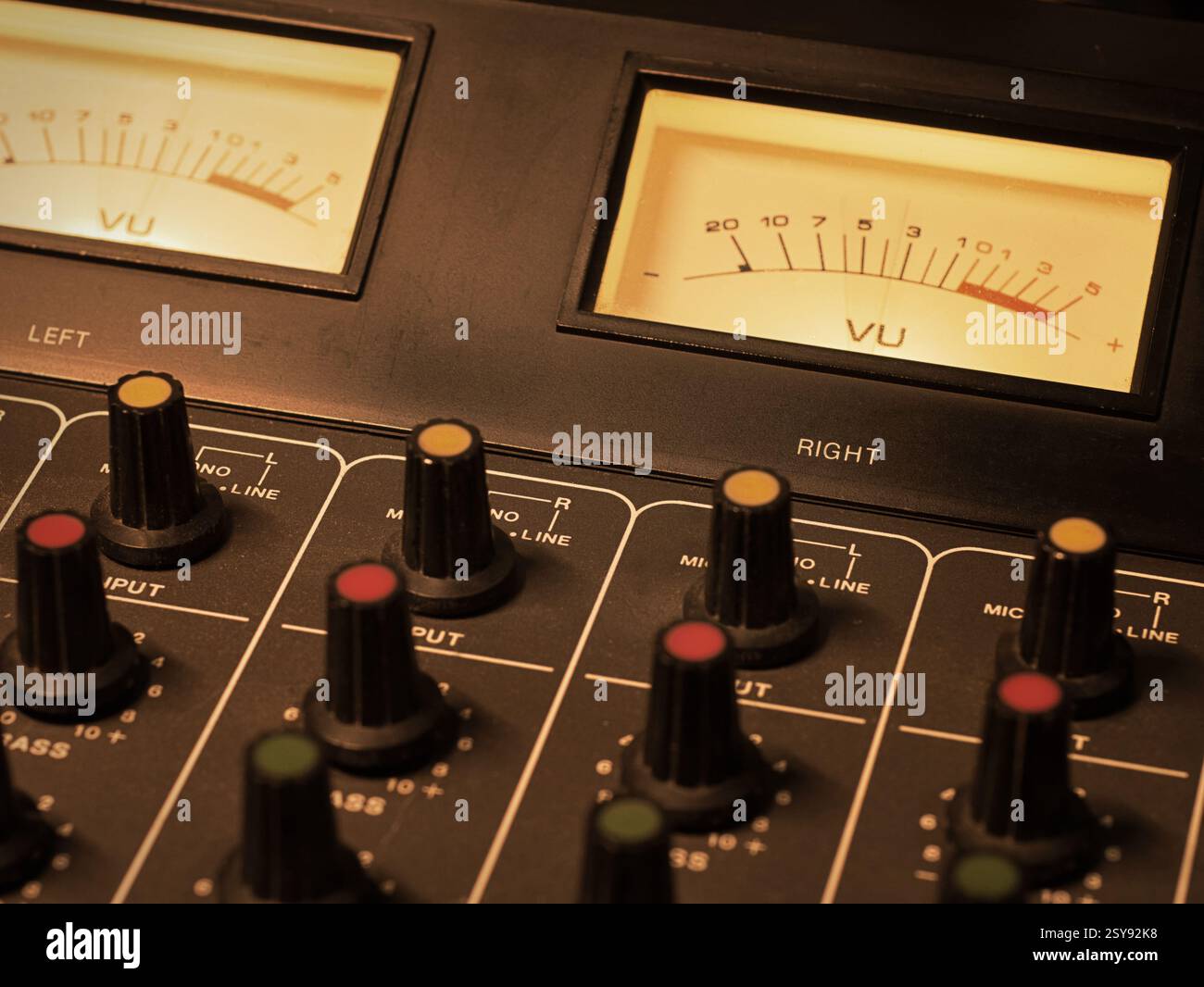 Detail of an analog studio mixer. Professional audio console with illuminated VU meters and ...