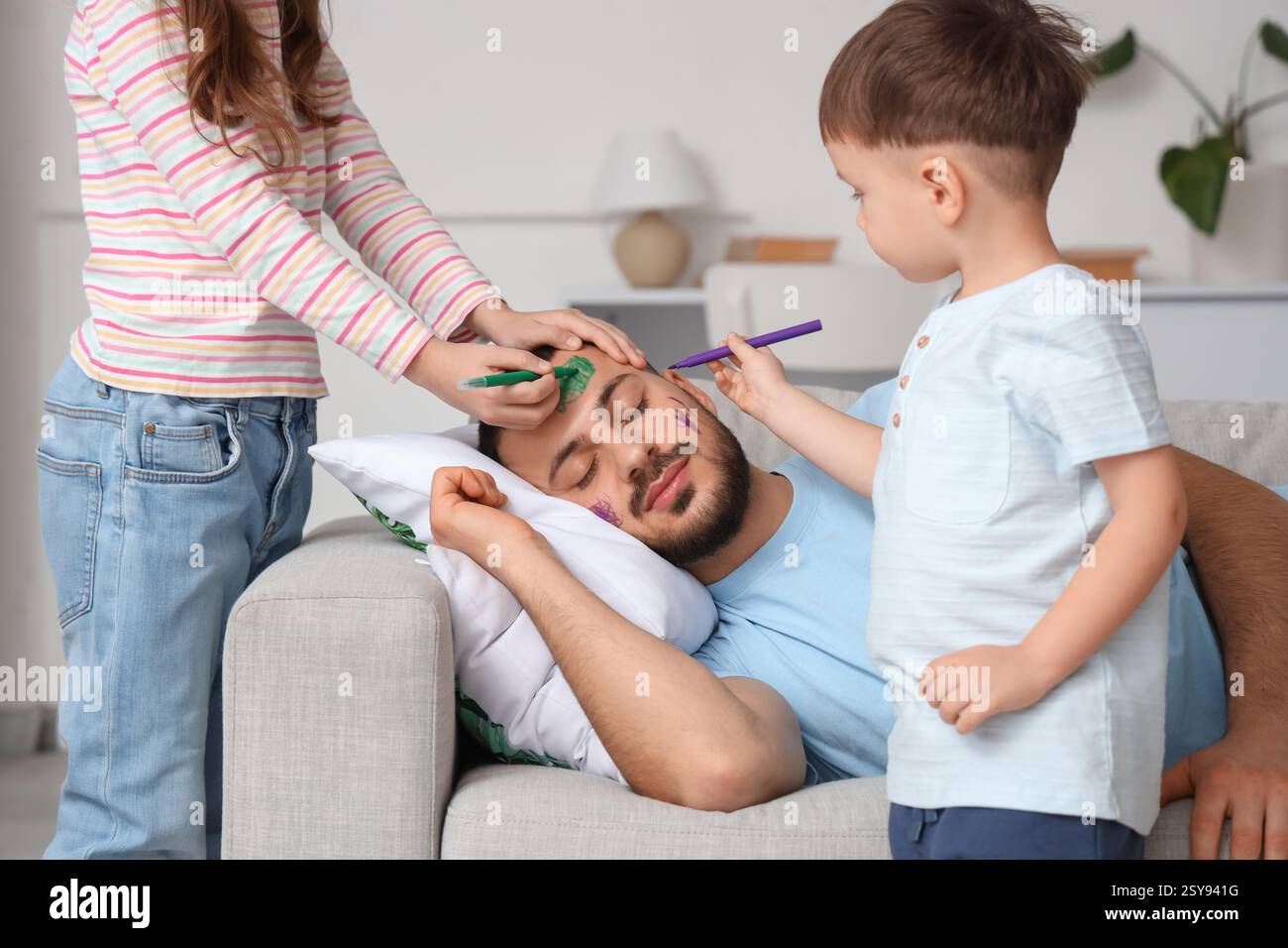 Little children painting their father's face while he sleeping at home ...
