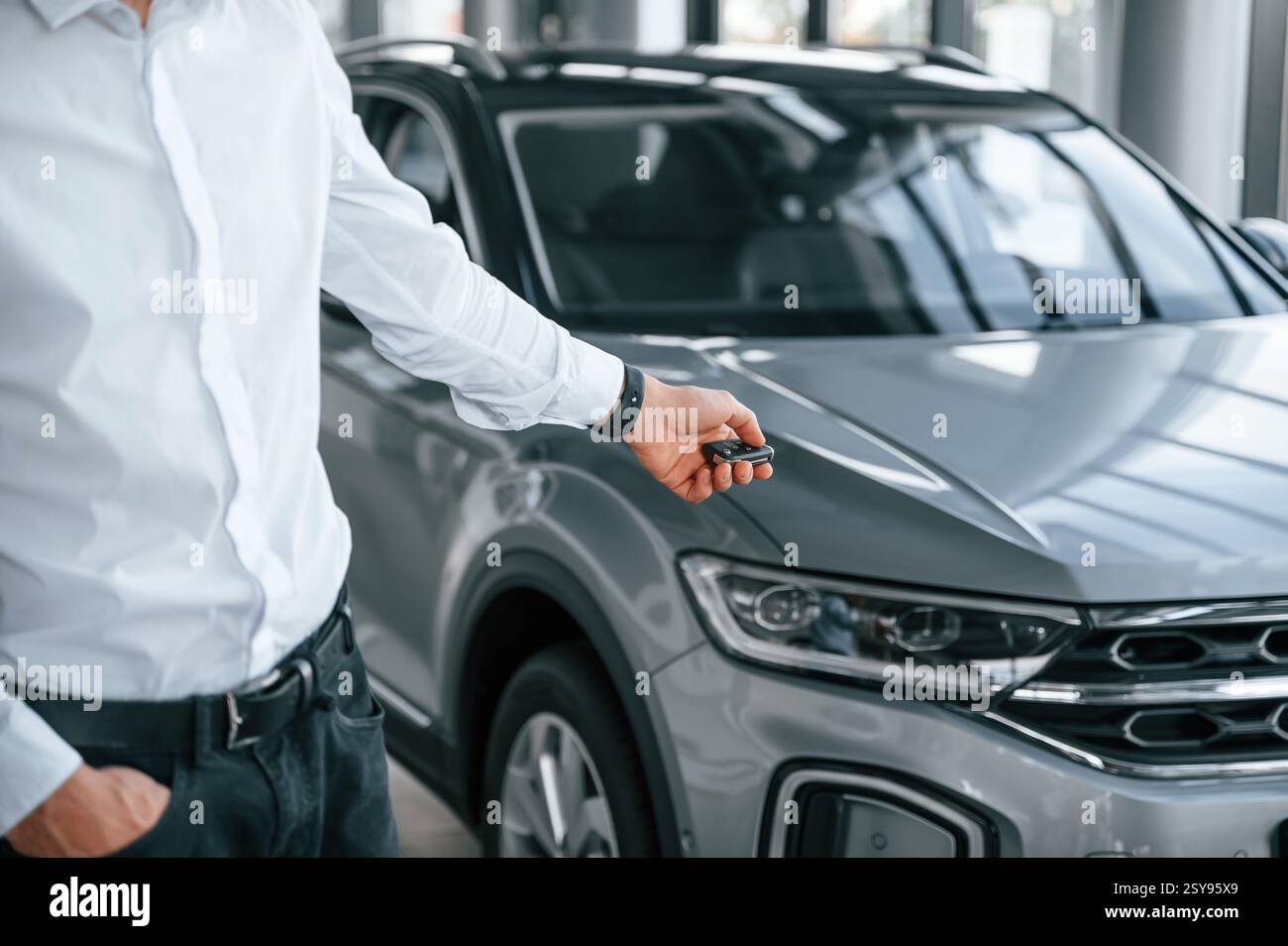 Closing the automobile by remote keys. Young man in white clothes is in ...