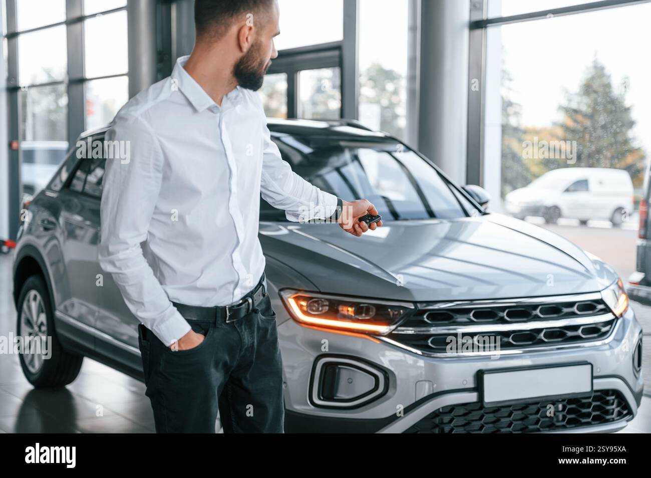 Closing the automobile by remote keys. Young man in white clothes is in ...