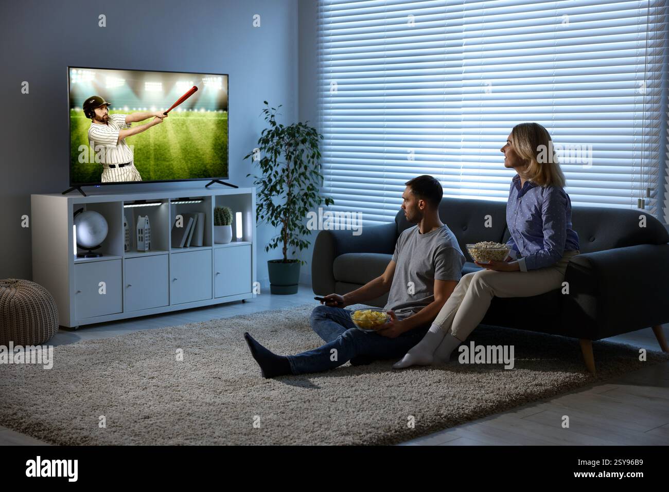 Couple watching baseball game on TV set at home Stock Photo - Alamy