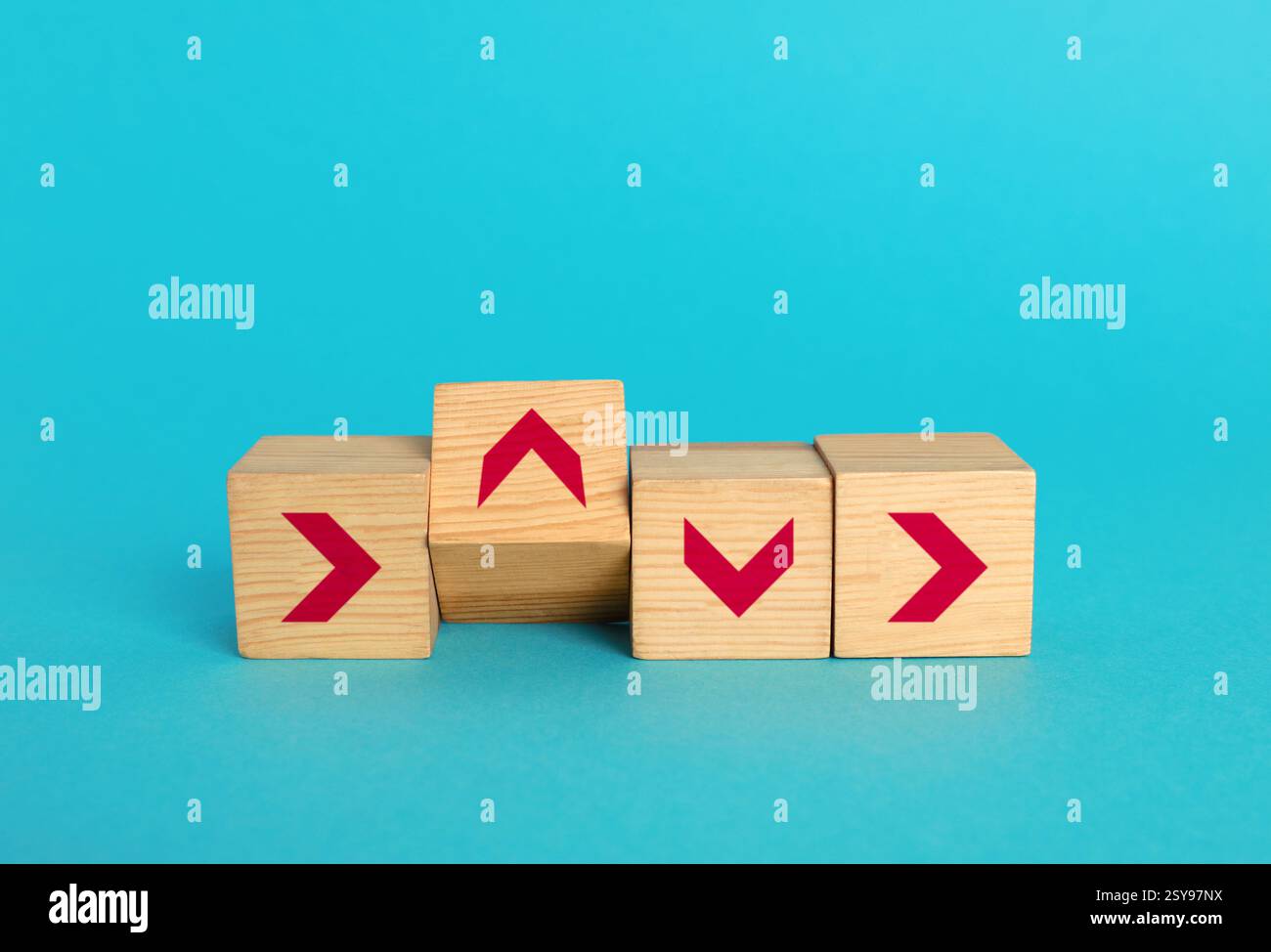 Wooden cubes with arrows pointing in different directions on light blue ...