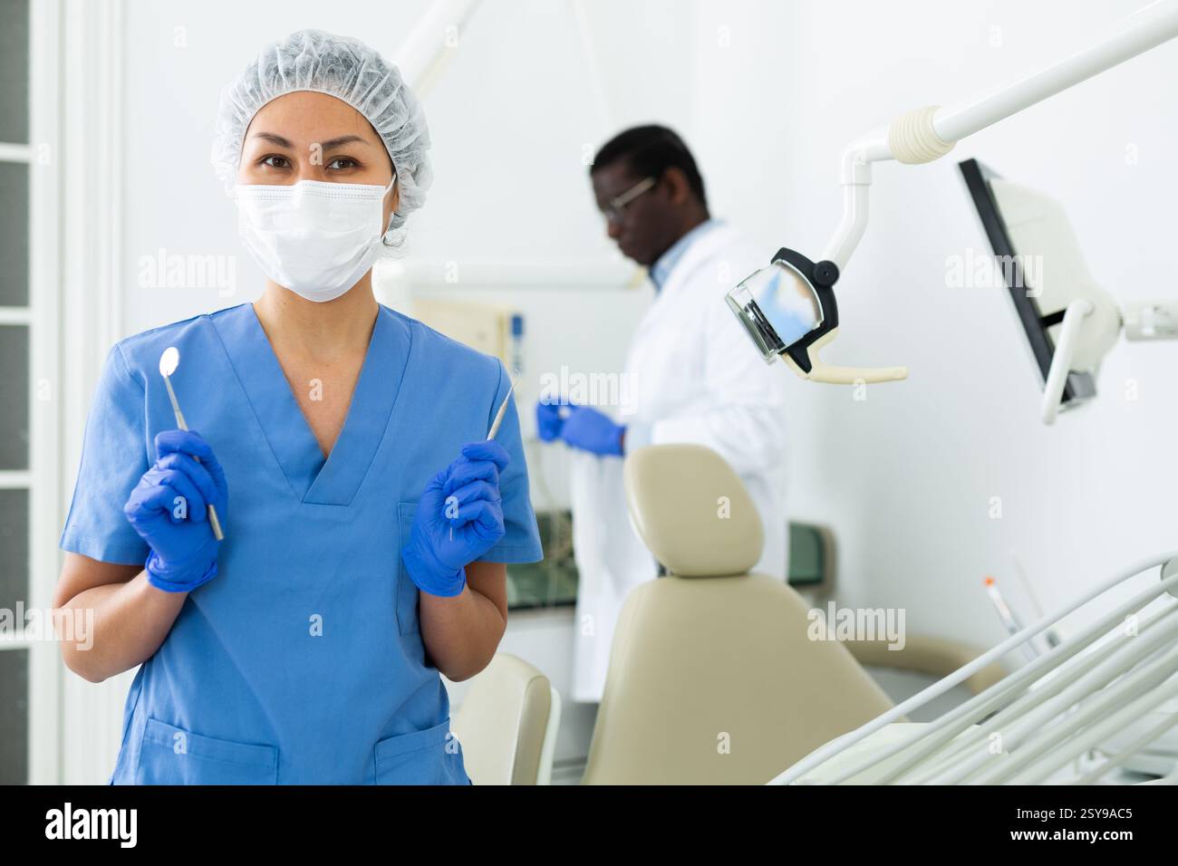 Female dentist standing in dental office with tools in hands Stock ...