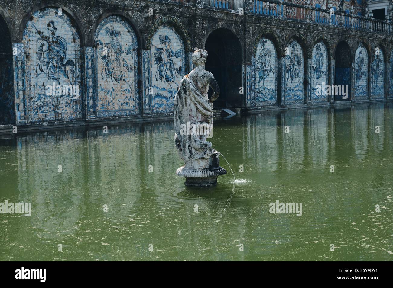 Stone statue stands in a green-hued pond, framed by intricate blue ...