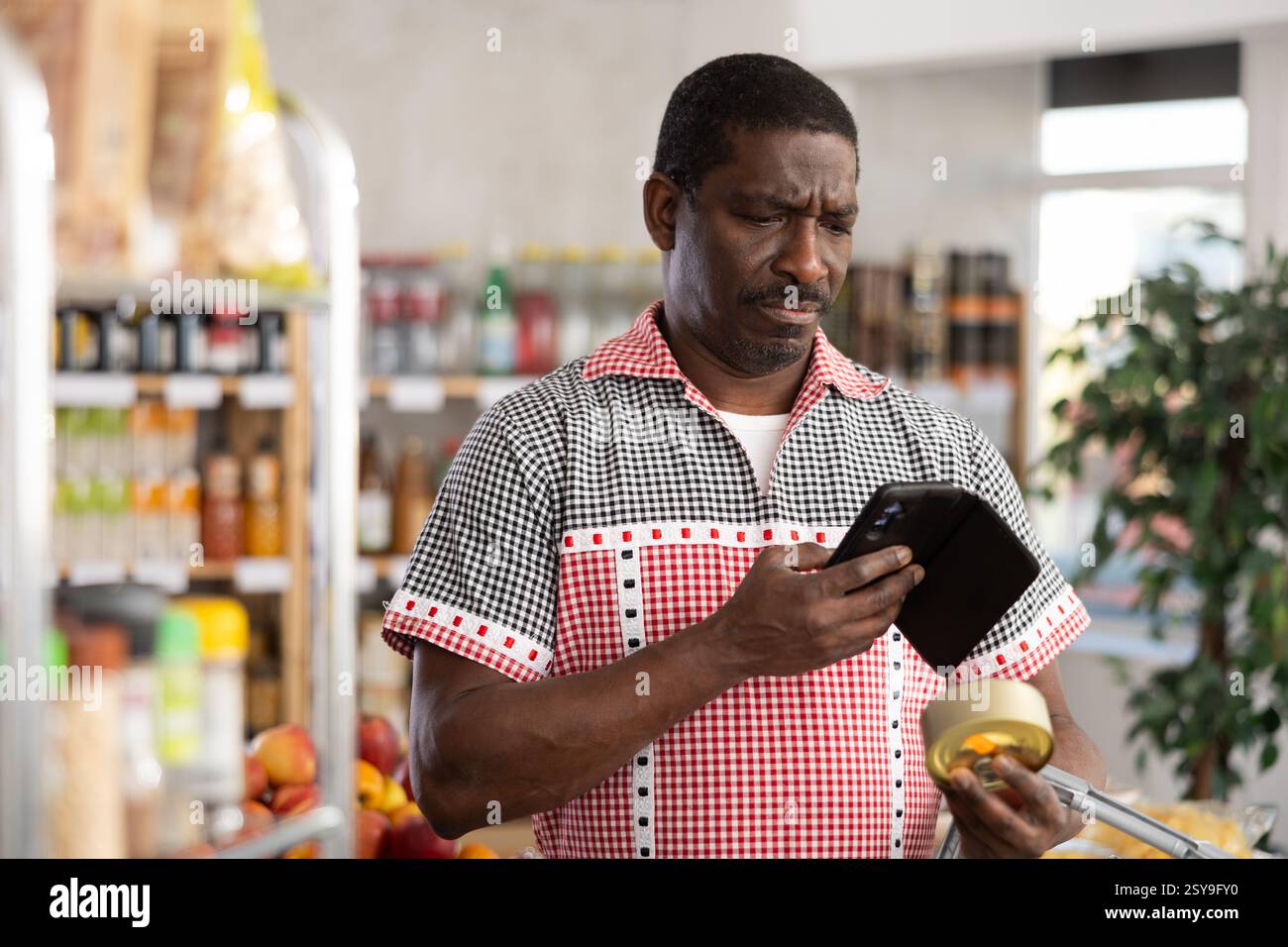 African man customer at shop scans QR code on tin cans of preserves ...