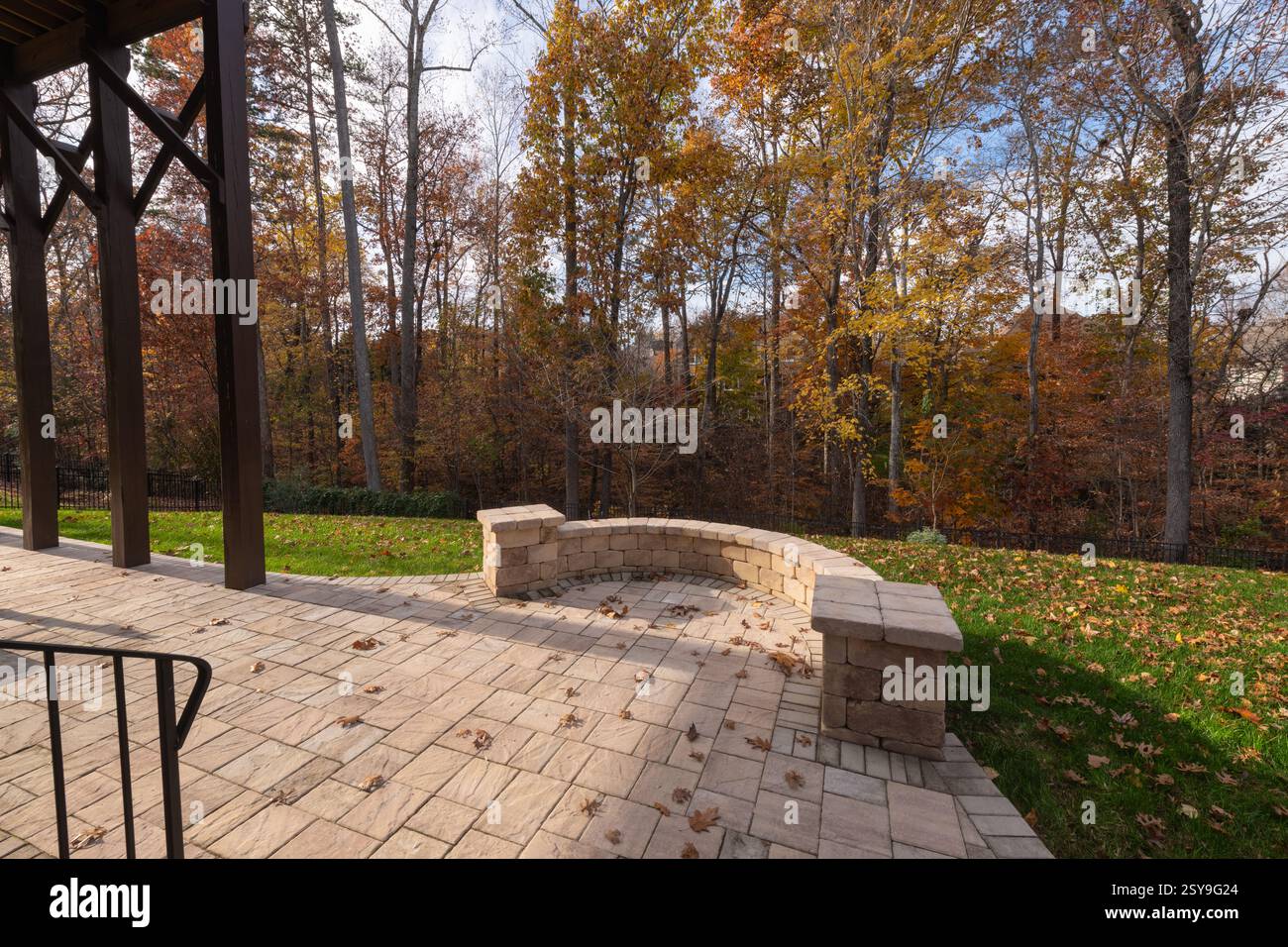 A backyard patio with stone pavers and a curved stone wall, framed by ...