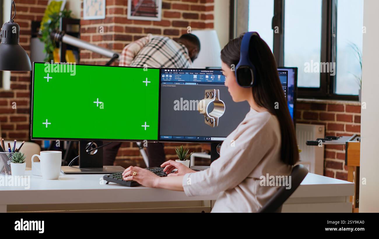 Software developer works in a modern office with green screen and dual ...