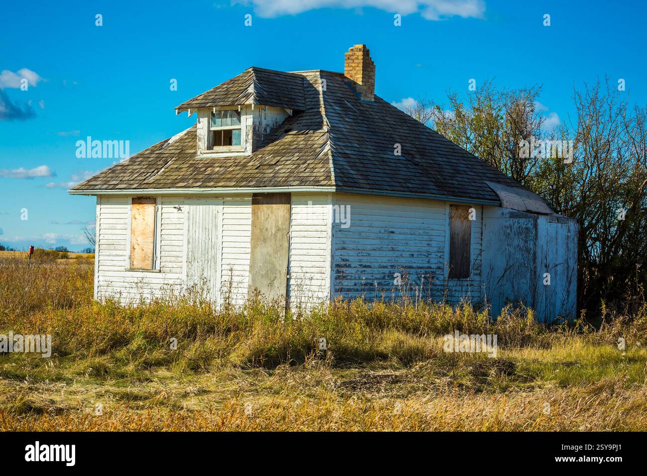 Small, old house with a slanted roof. The roof is missing shingles. The ...
