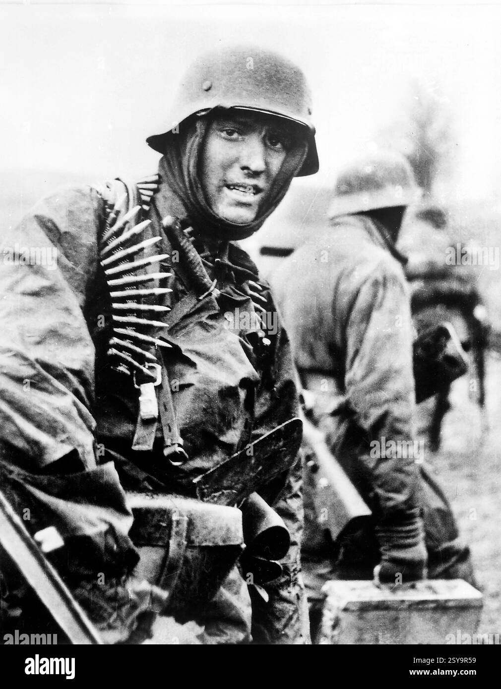 Nazi soldier, heavily armed, carrying ammunition boxes forward with ...