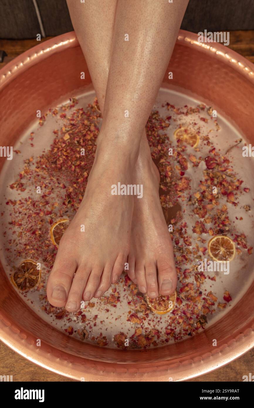 Feet soaking in milky foot bath with flowers and slices of sliced fruit ...