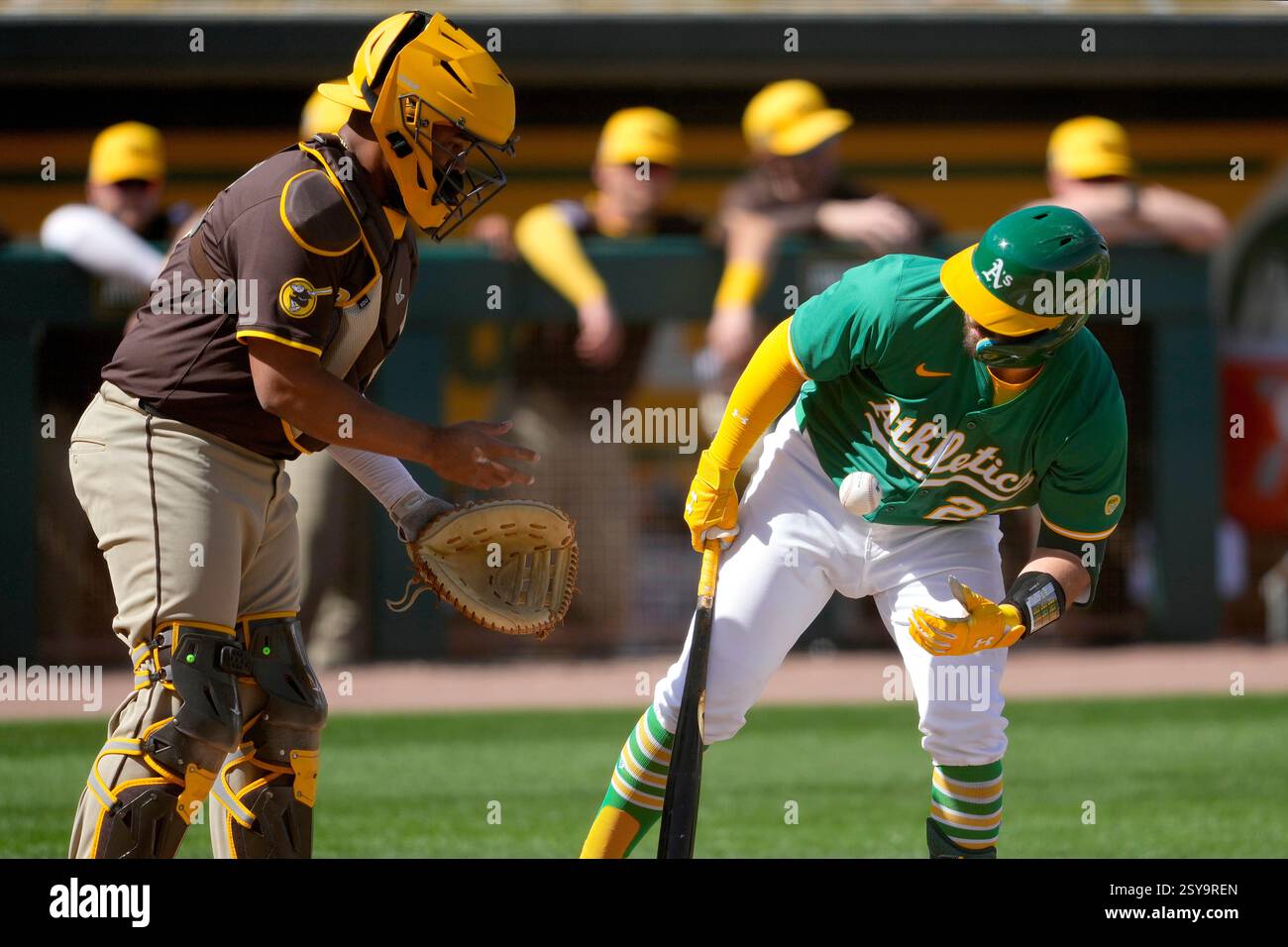 Athletics hitter Shea Langeliers, right, tosses the baseball back to ...