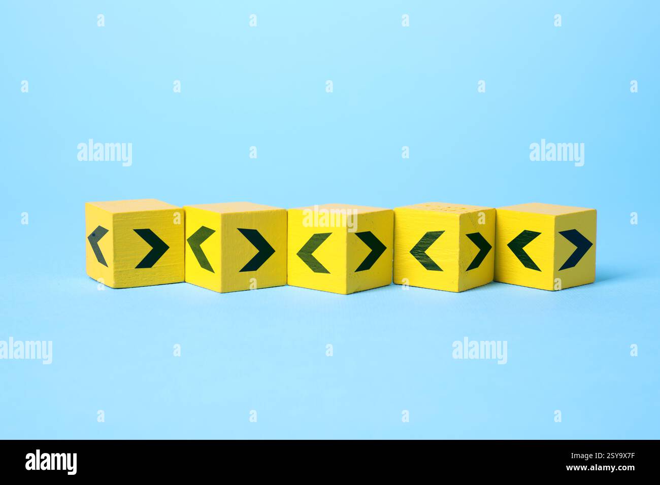Yellow cubes with black arrows on light blue background Stock Photo - Alamy