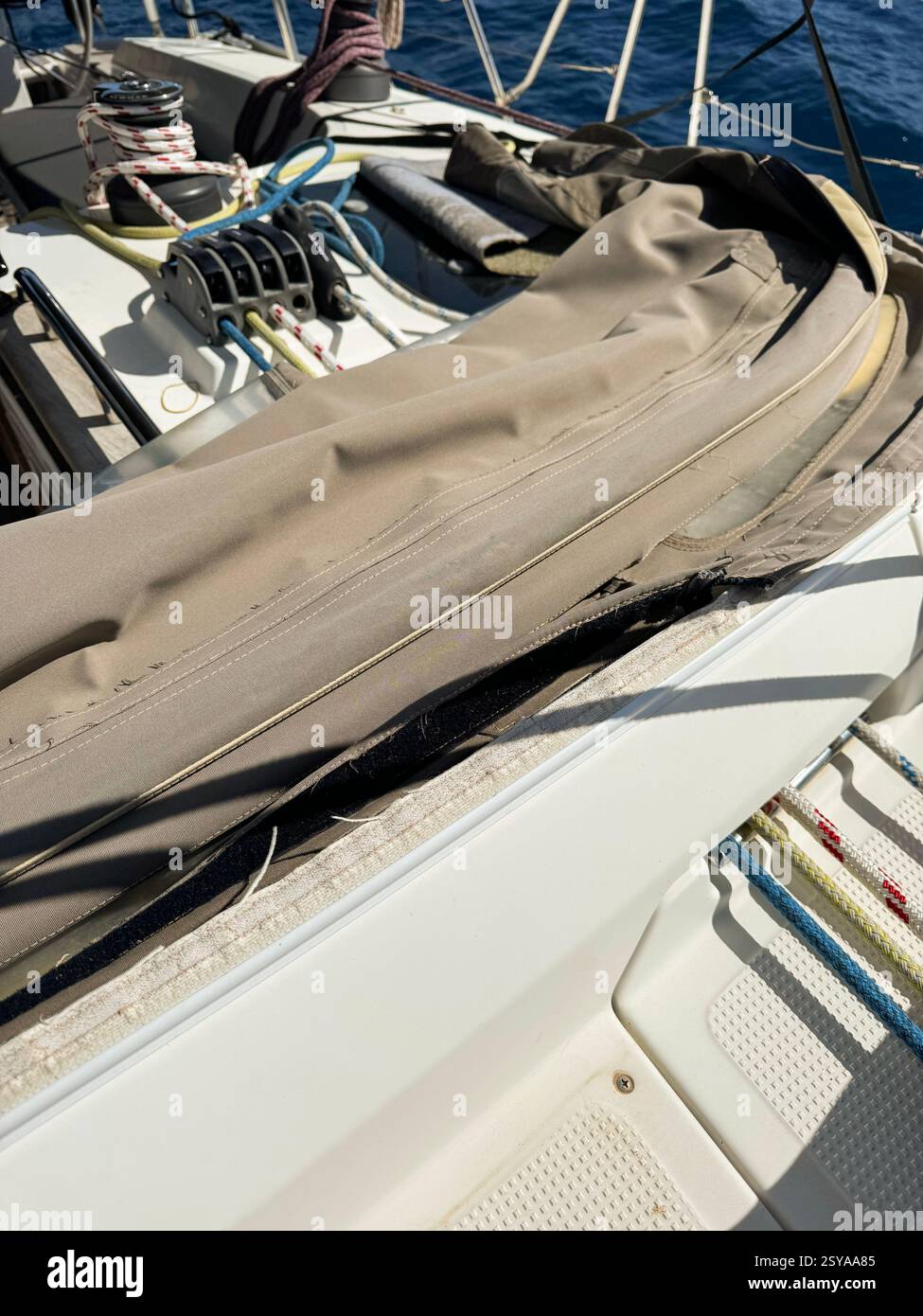 A sailboat deck shows damaged fabric, exposing threads on a sunny day ...
