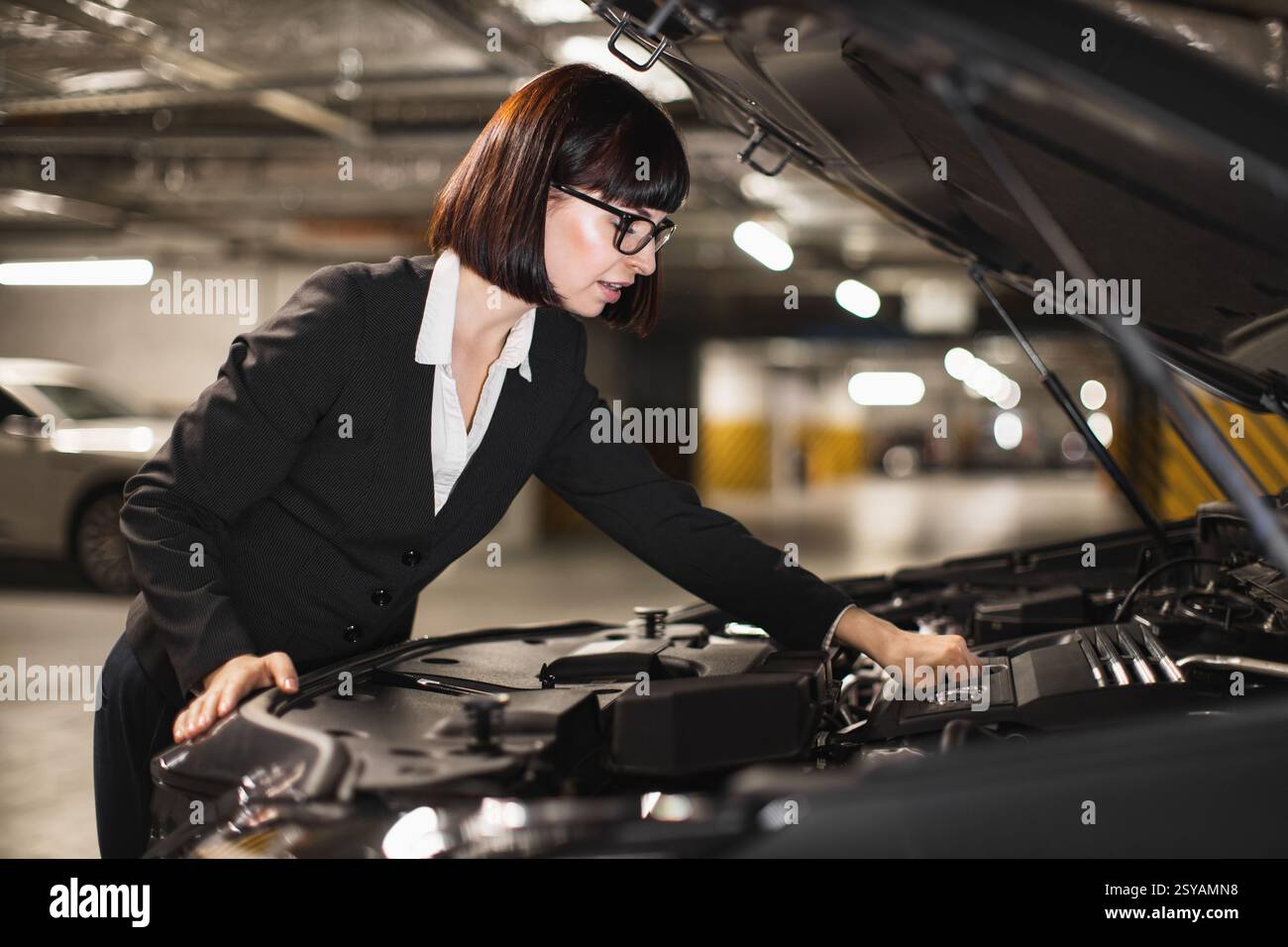 Caucasian businesswoman in formal attire fixes car engine in ...