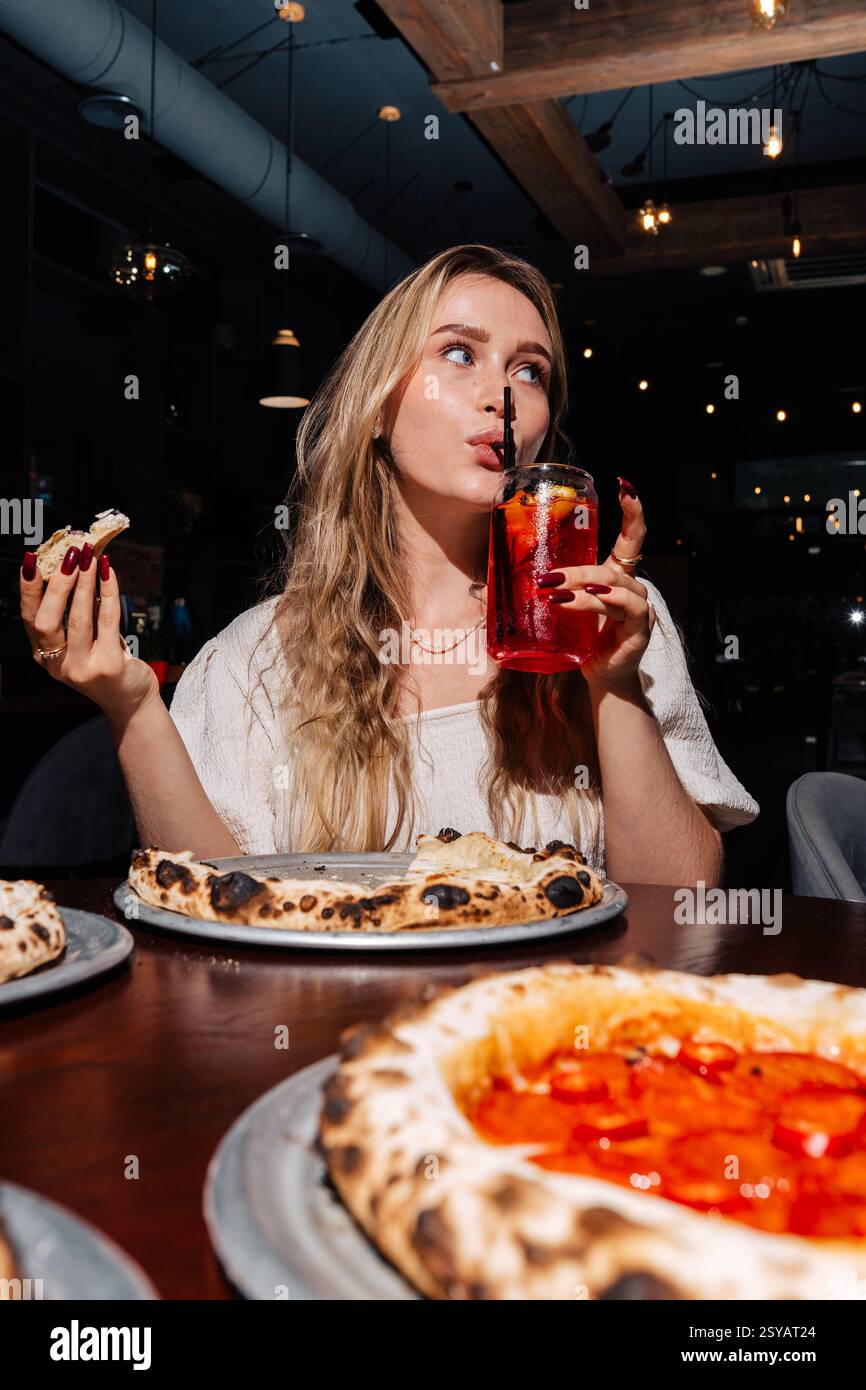 Woman sipping a refreshing berry lemonade and savoring wood-fired ...