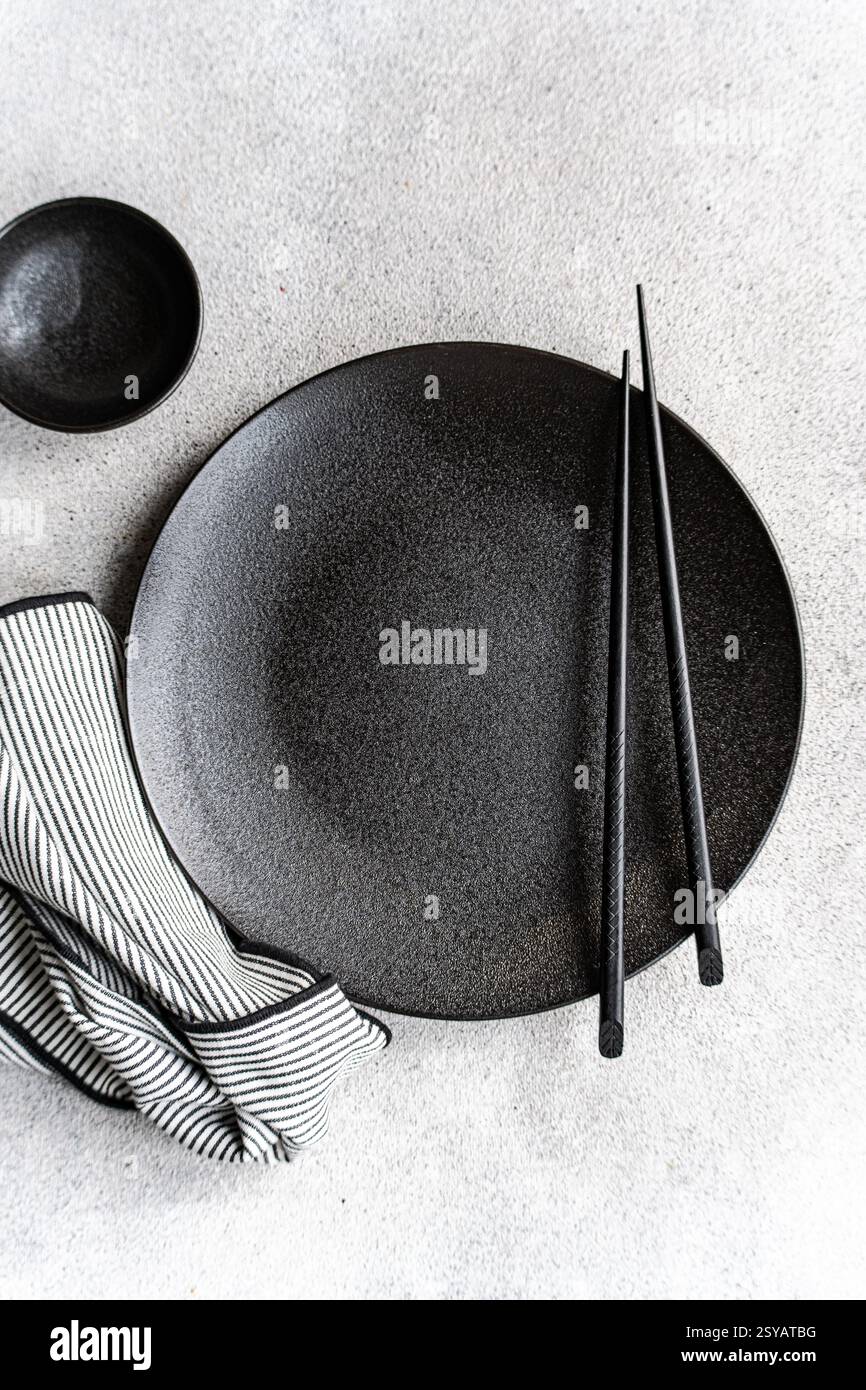 A minimalist black and white table setting featuring a textured dark ...