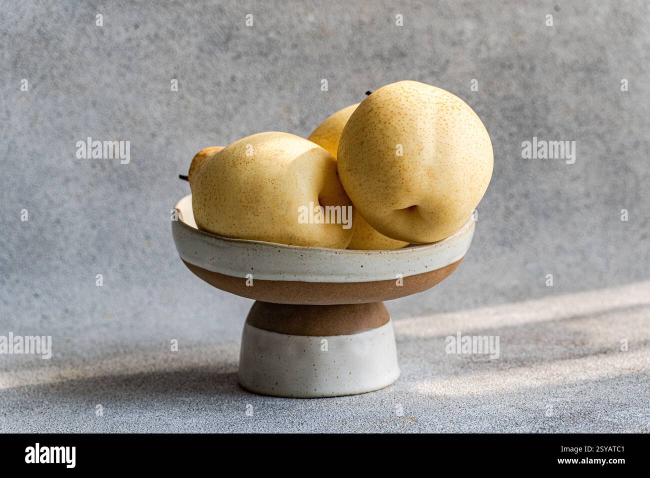 Three Chinese white pears are elegantly displayed in a ceramic bowl ...