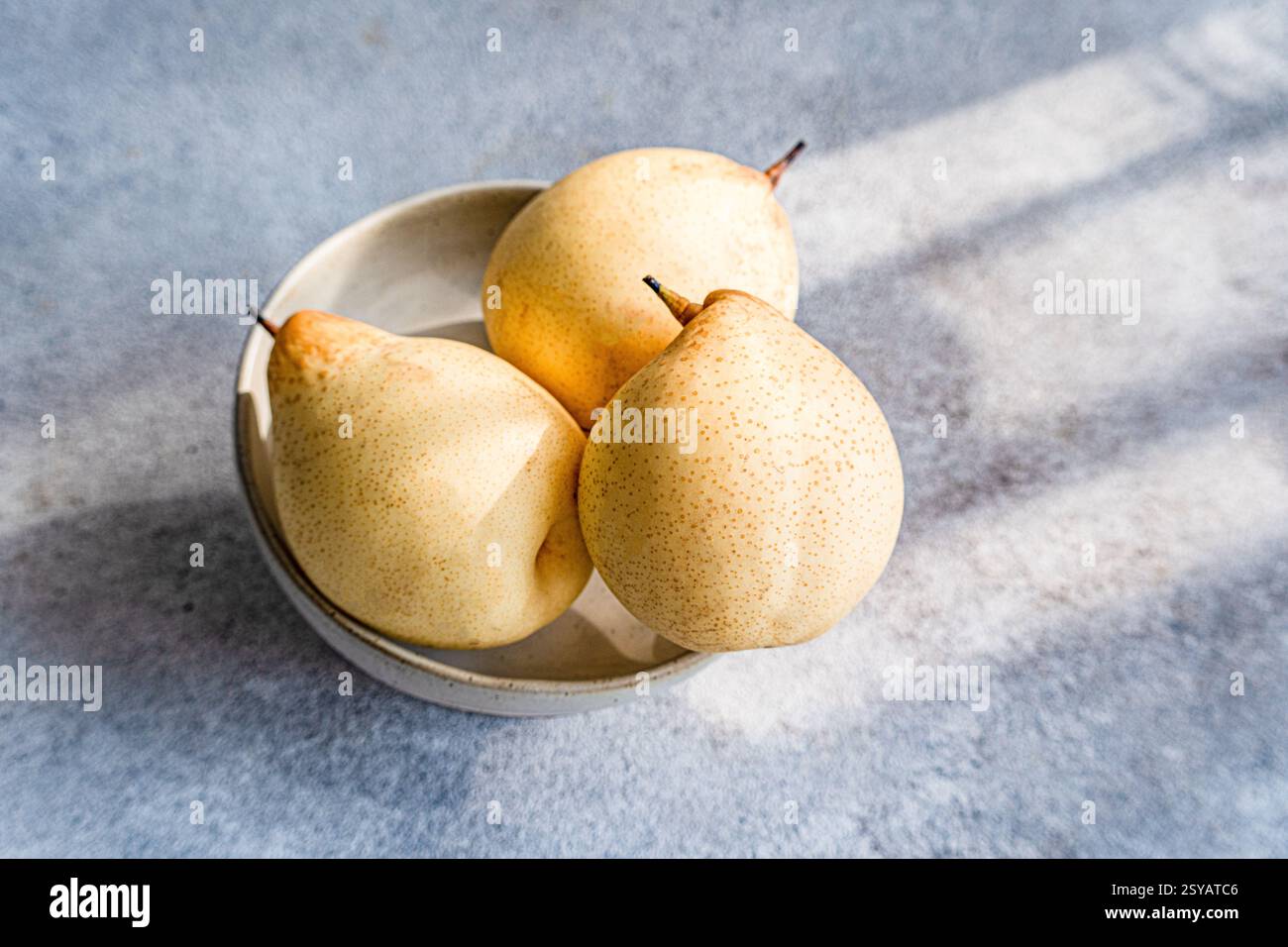Three Chinese white pears in a bowl are placed on a textured surface ...