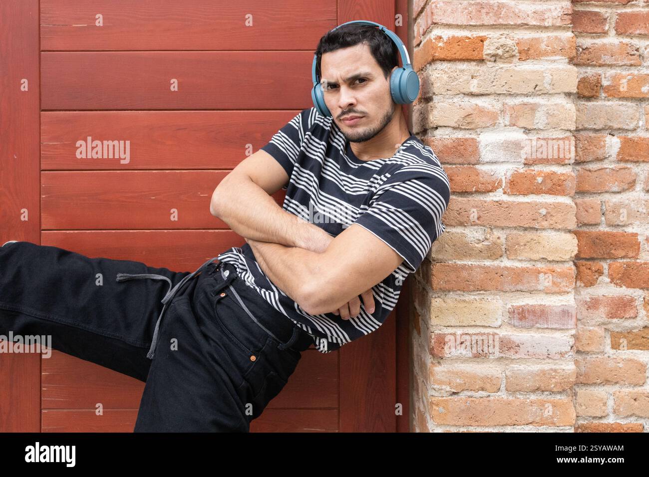 Young Cuban man in a striped shirt and headphones striking a dance pose ...