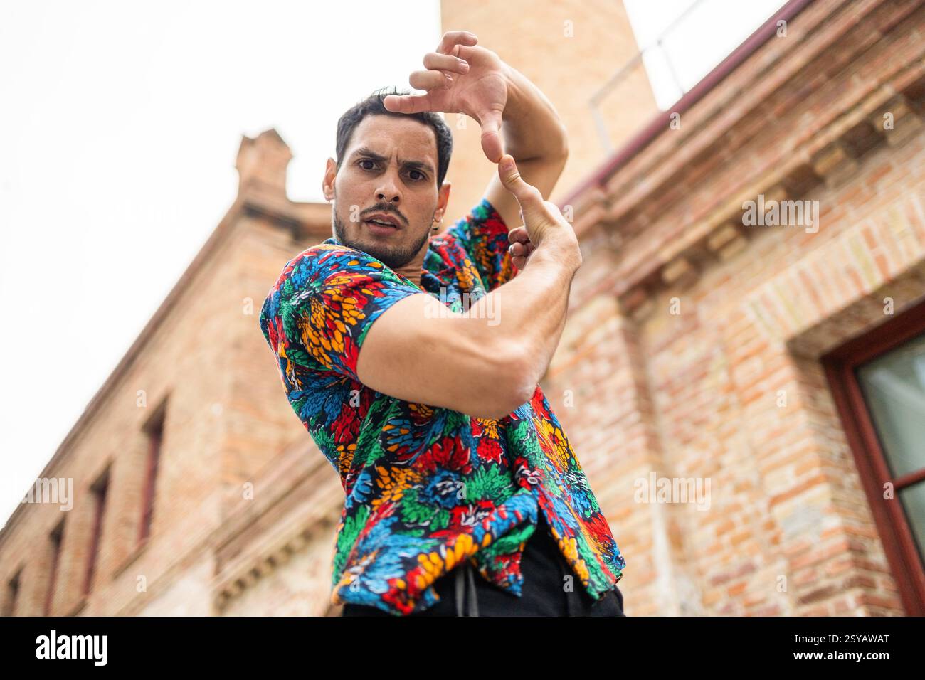 A male dancer in a vibrant, patterned shirt strikes a dynamic pose ...