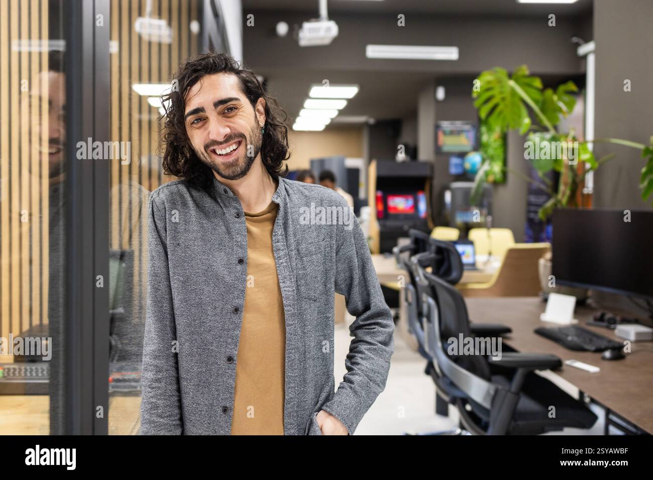 A man smiling in a contemporary office setting, surrounded by modern ...