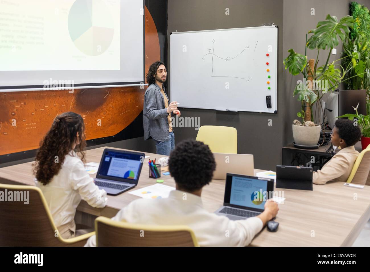 A team engaged in a dynamic office meeting. A presenter explains data ...