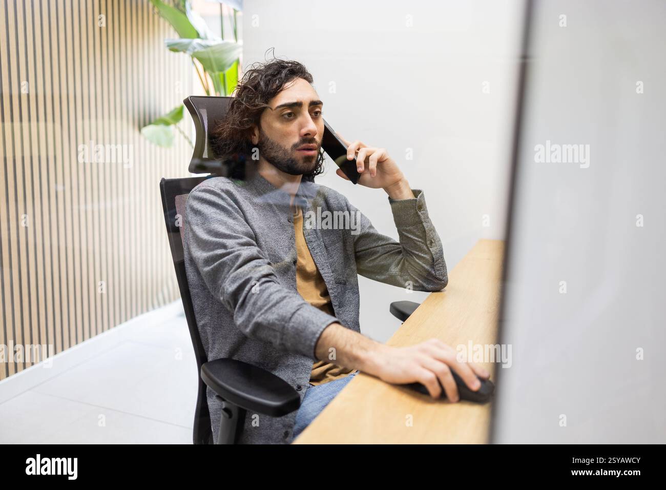 A focused professional sits at a sleek office desk, multitasking with a ...