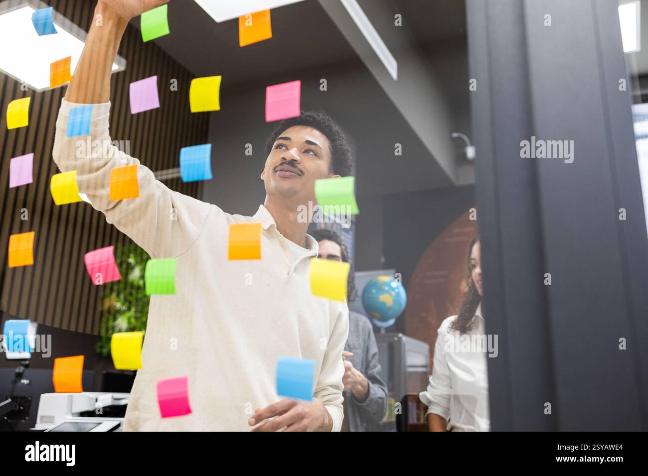 A group of professionals brainstorms using vibrant sticky notes on ...