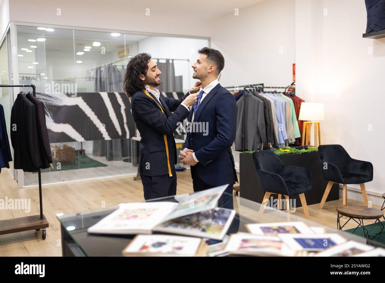 A tailor making final adjustments on a client suit in a modern suit ...