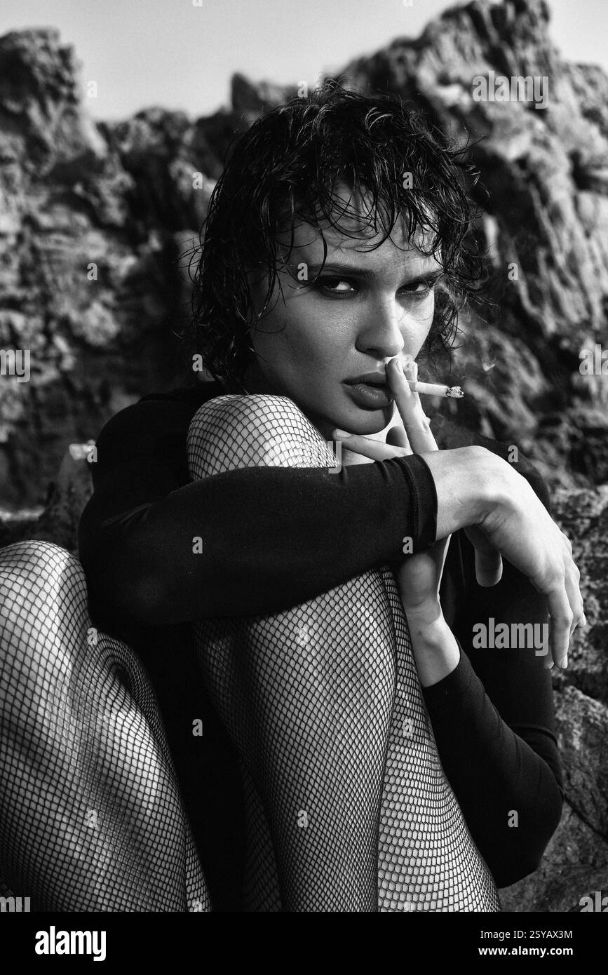 A striking portrait of a woman in a fishnet outfit, holding a cigarette ...
