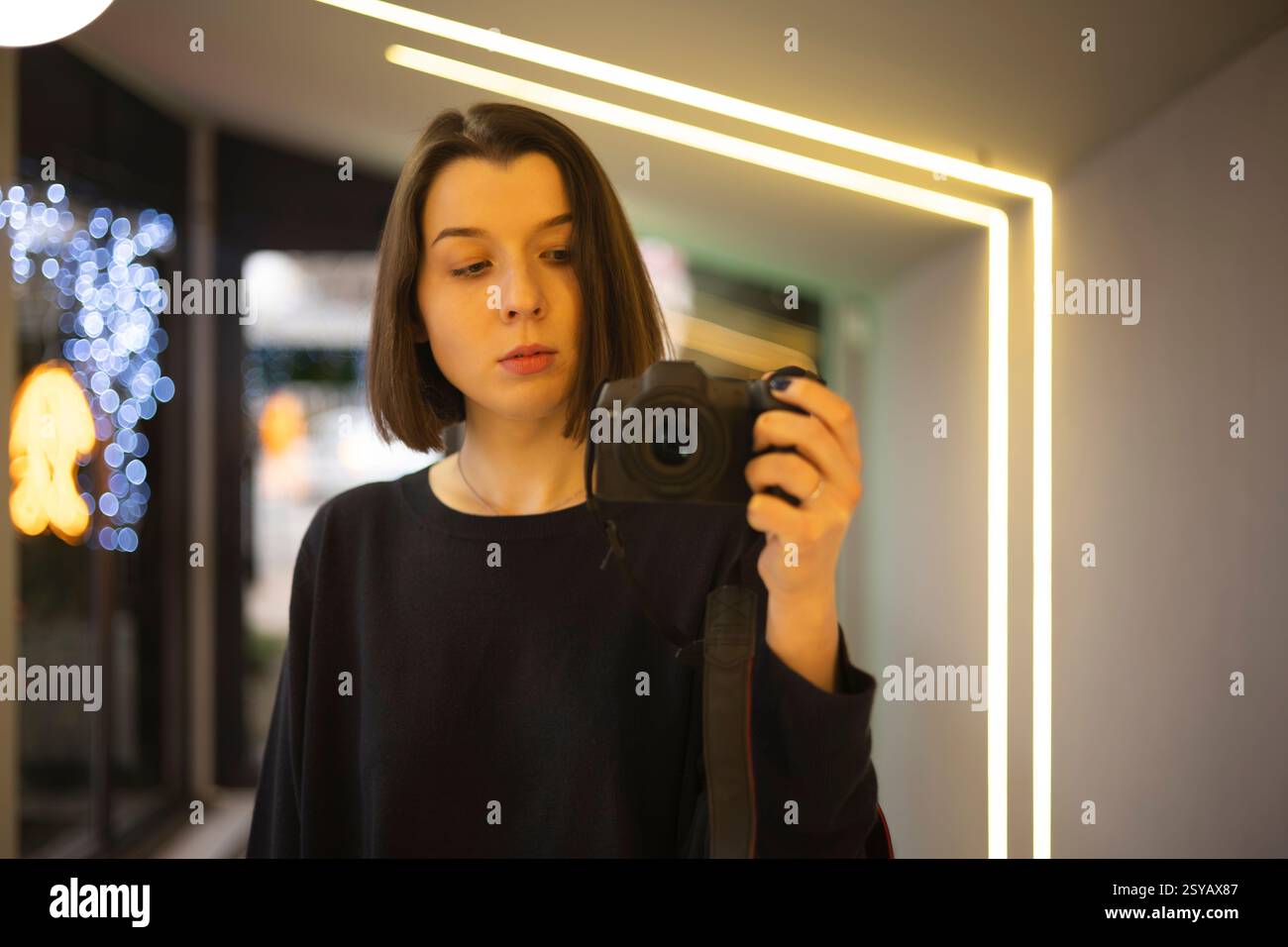 A woman capturing a self-portrait using a DSLR camera in a well-lit ...
