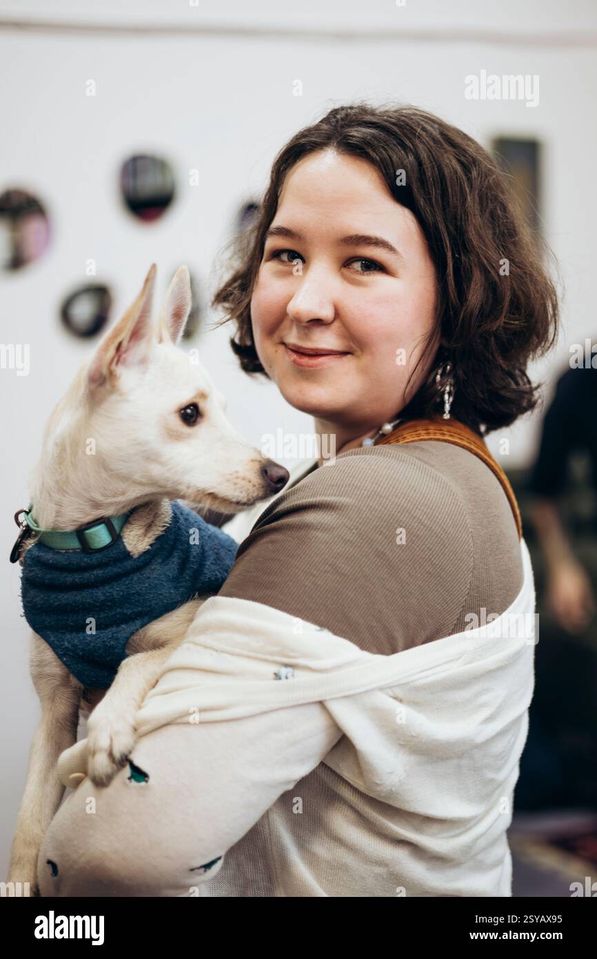 A young woman smiles warmly as she holds her adorable dog in a cozy ...