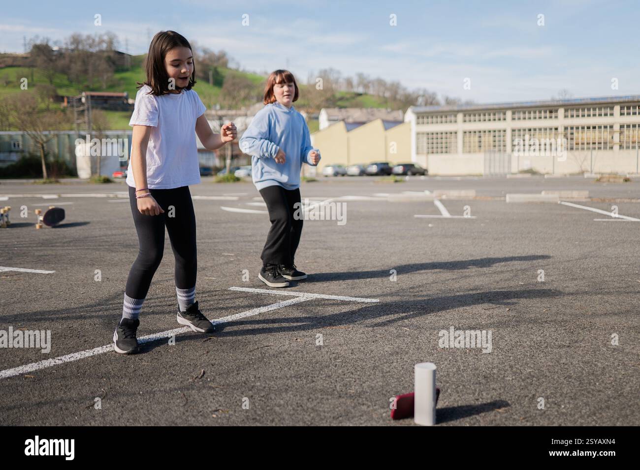 Two friends play a fun game outdoors in an empty parking lot under ...