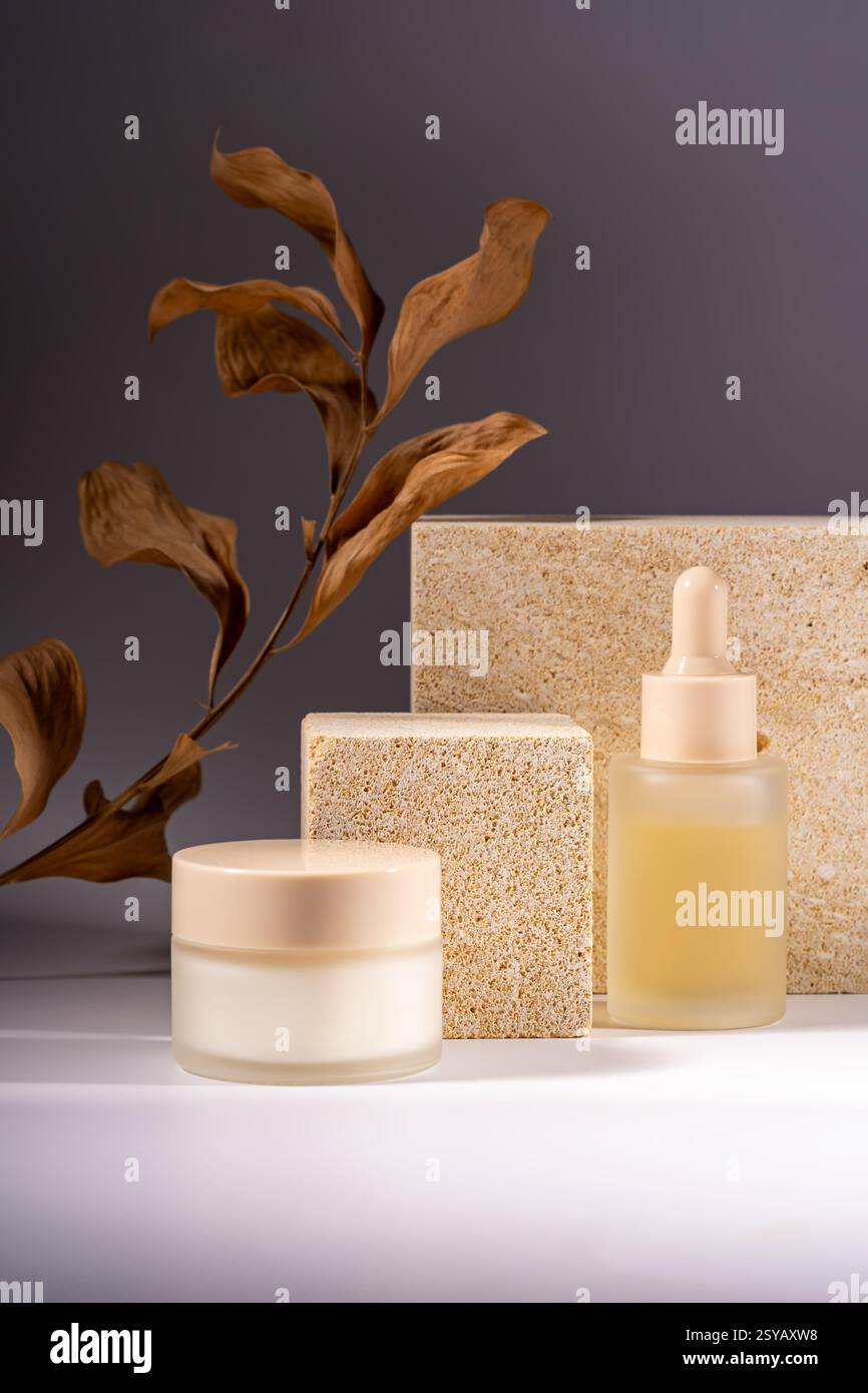 Aesthetic display of cosmetic bottles and cream jars on speckled stone ...