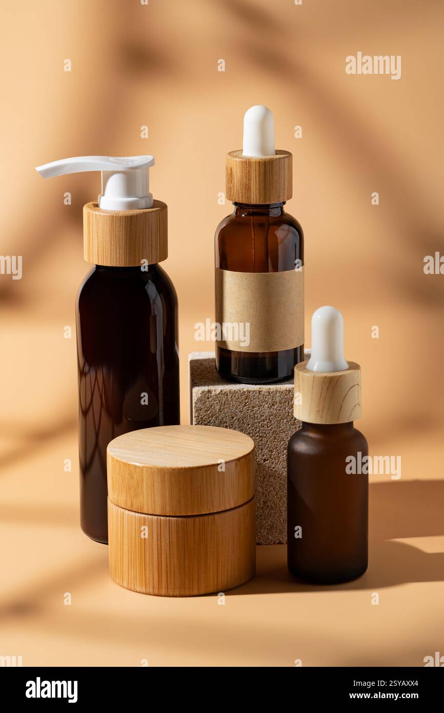 A selection of cosmetic bottles with wooden caps on a beige background ...