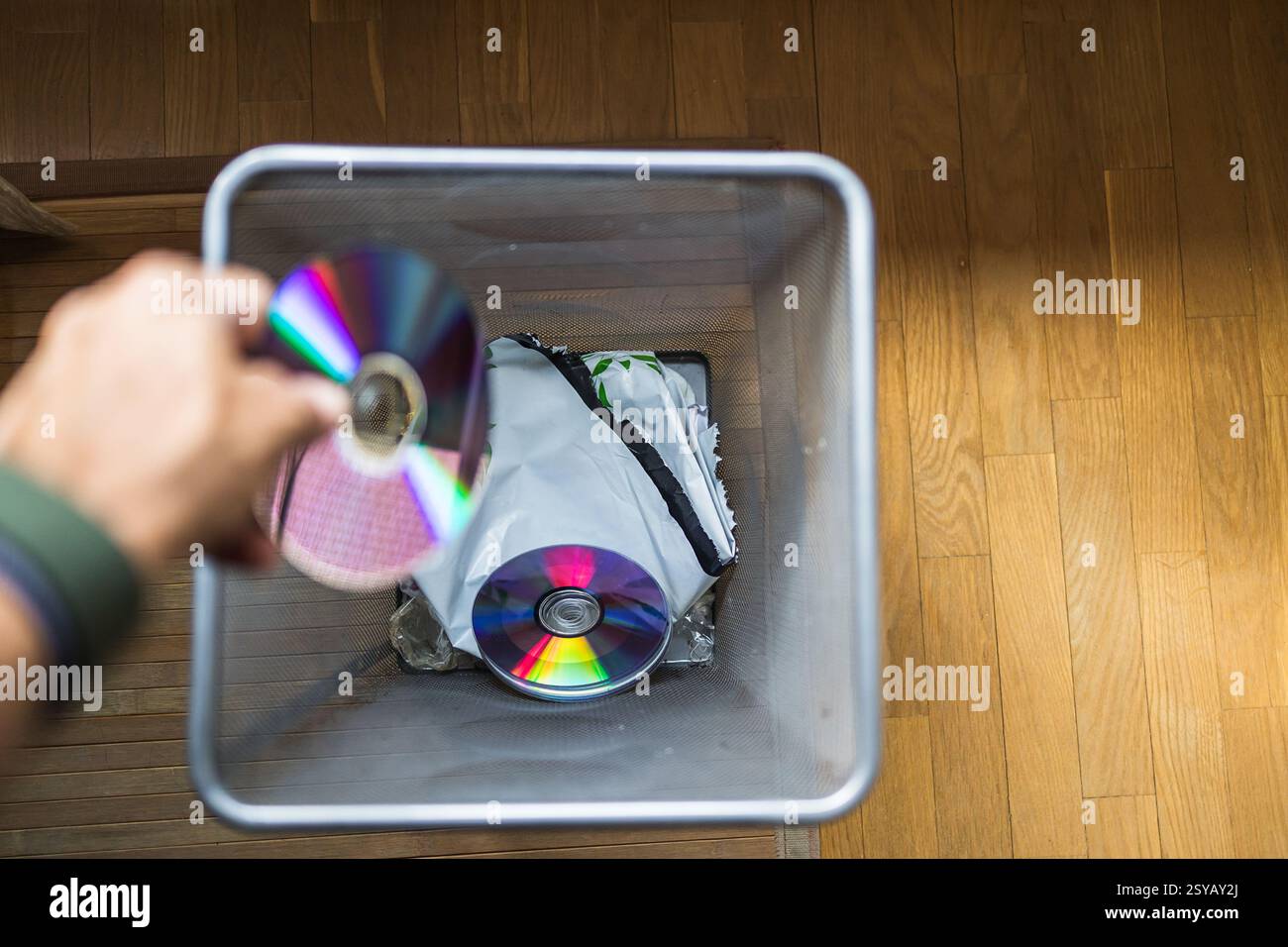 A hand discards CDs into a trash bin, symbolizing the shift from ...