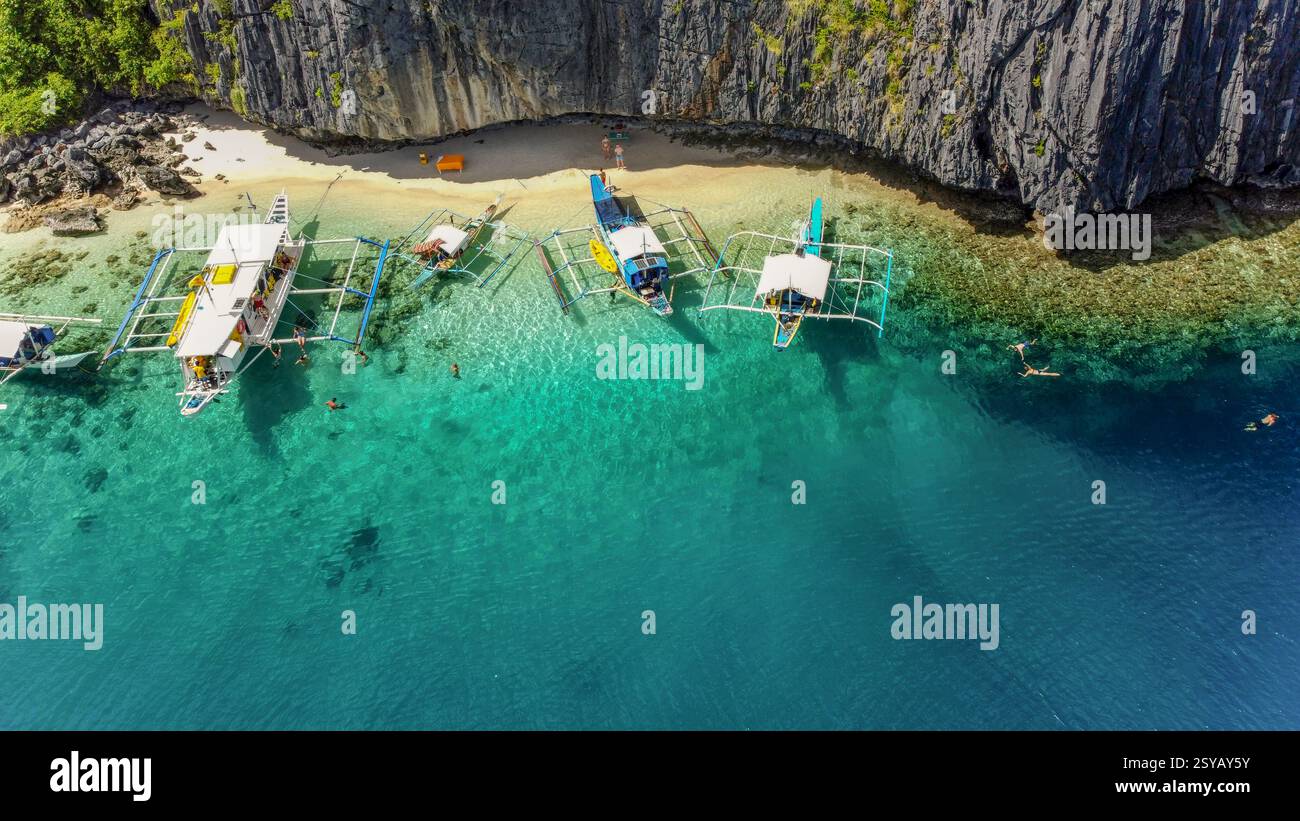 Aerial view of colorful tourist boats anchored at a secluded beach ...