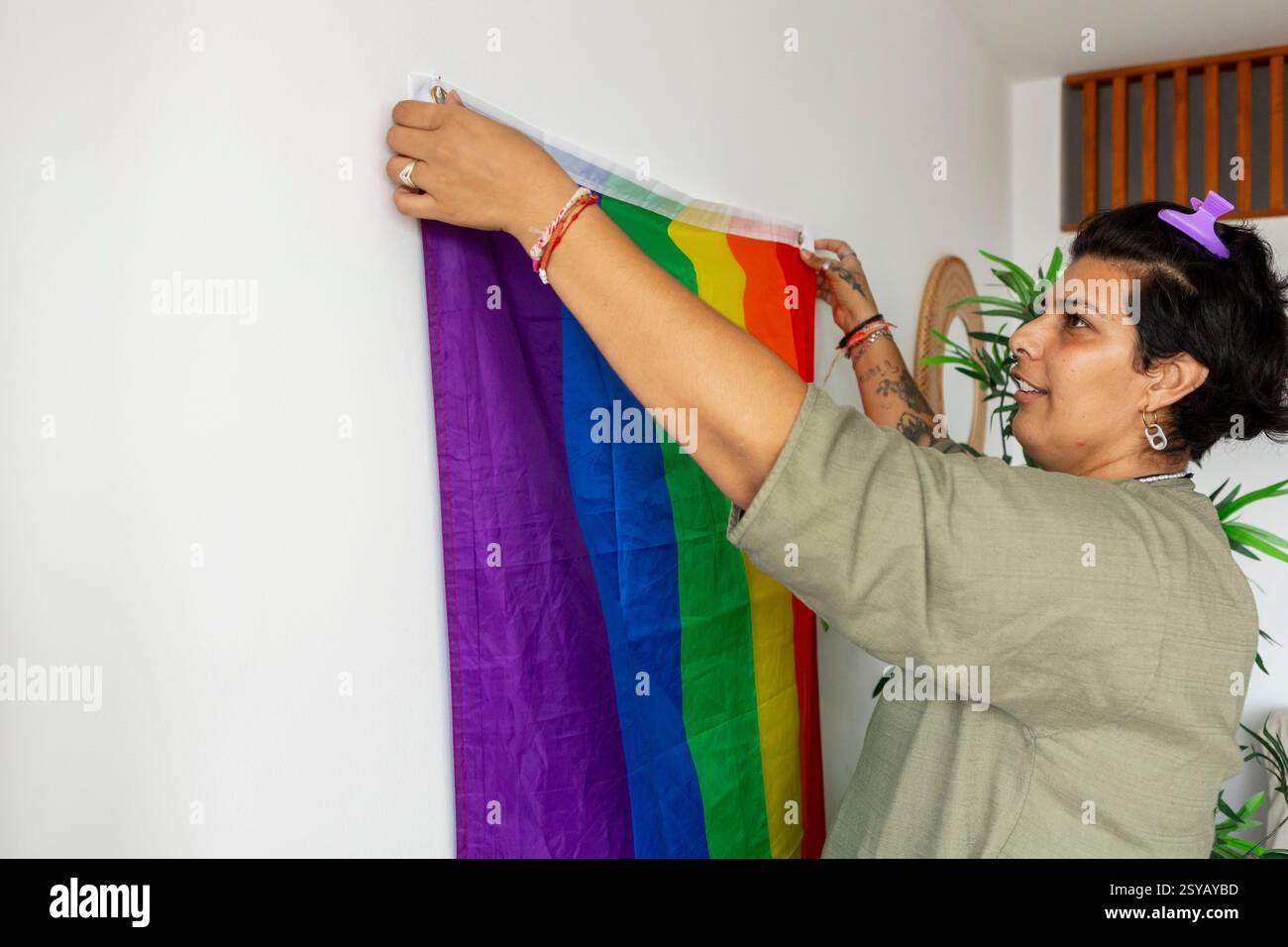 A trans woman joyfully decorating her new home with a rainbow pride ...