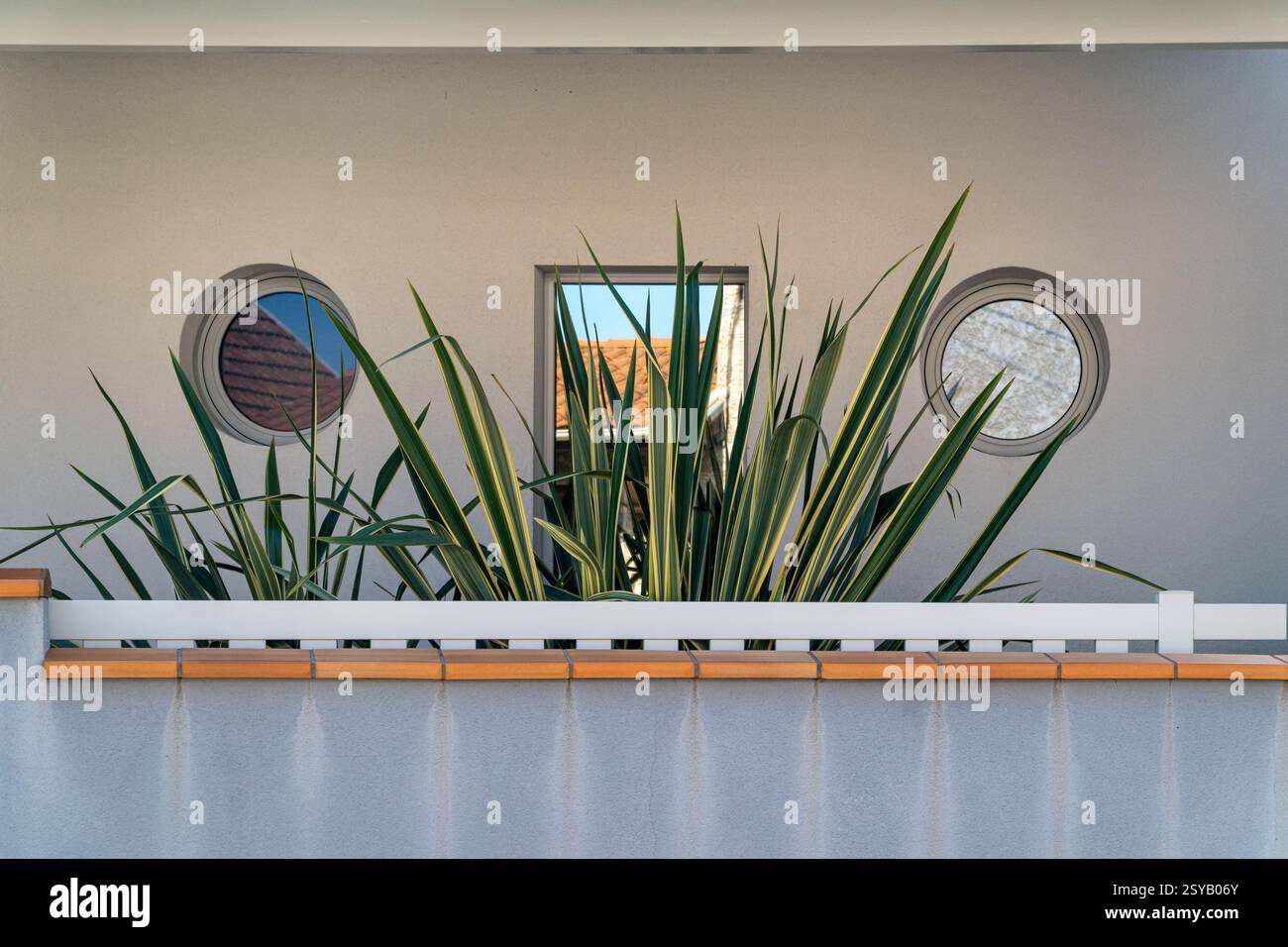 A modern home facade features a balcony lined with vibrant tropical ...