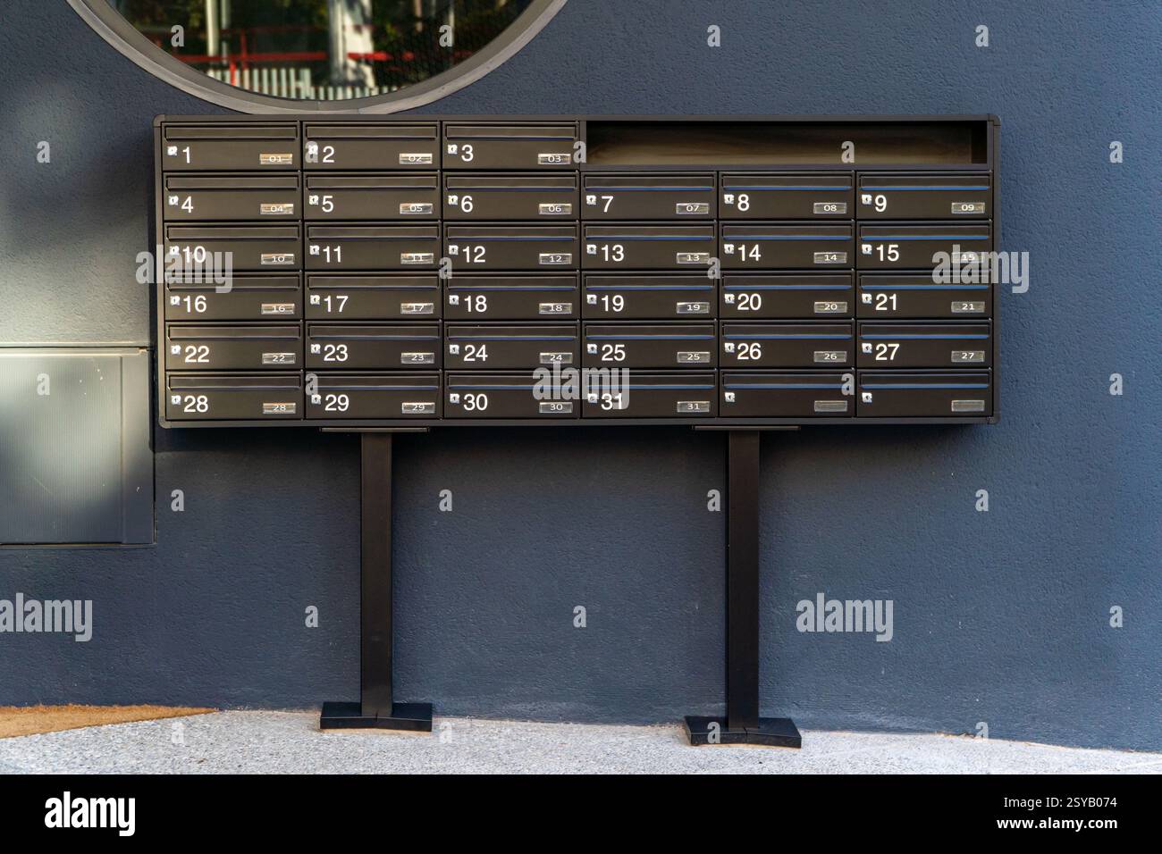 A modern mailbox unit featuring rows of dark metallic boxes labeled ...
