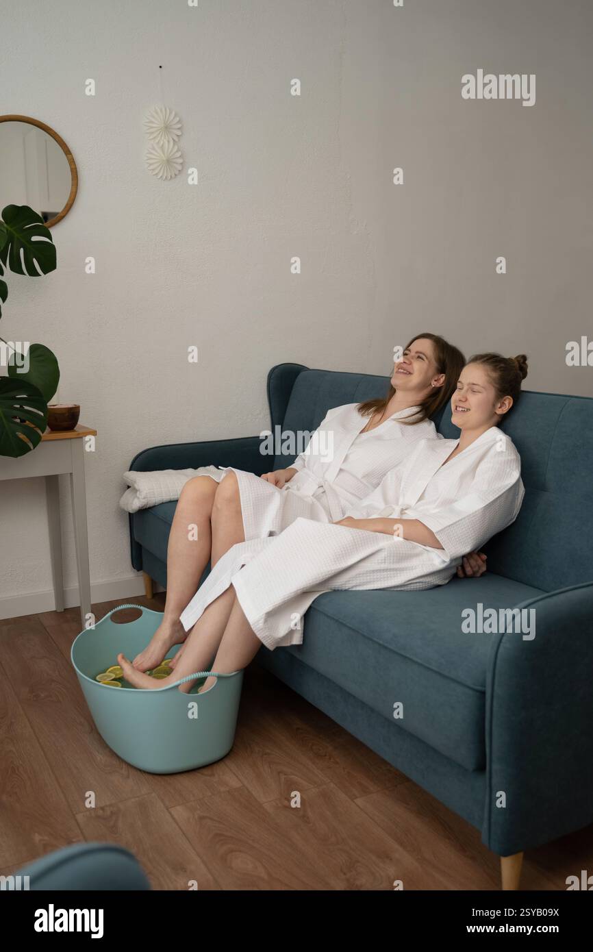 Mother and daughter enjoy quality time with a home spa session. Clad in ...