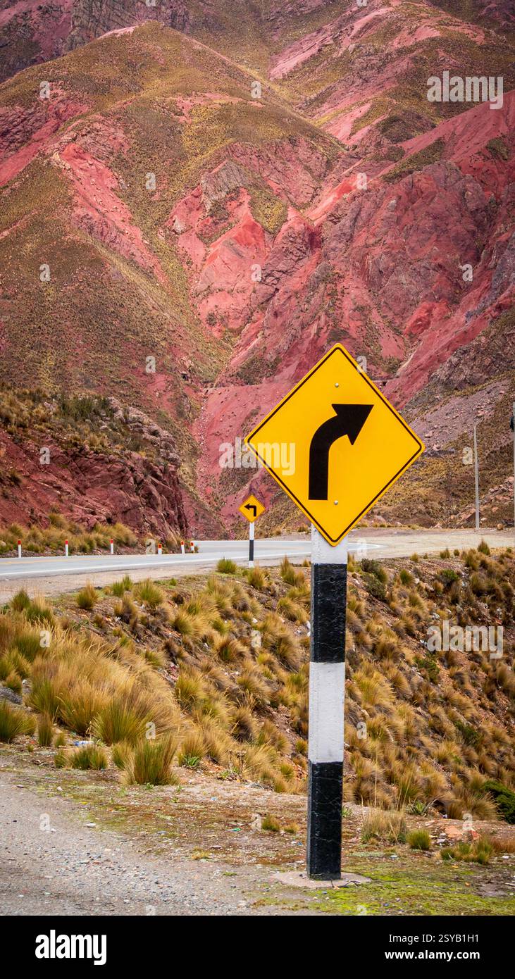 A road sign indicating a curve stands before stunning red-striped ...