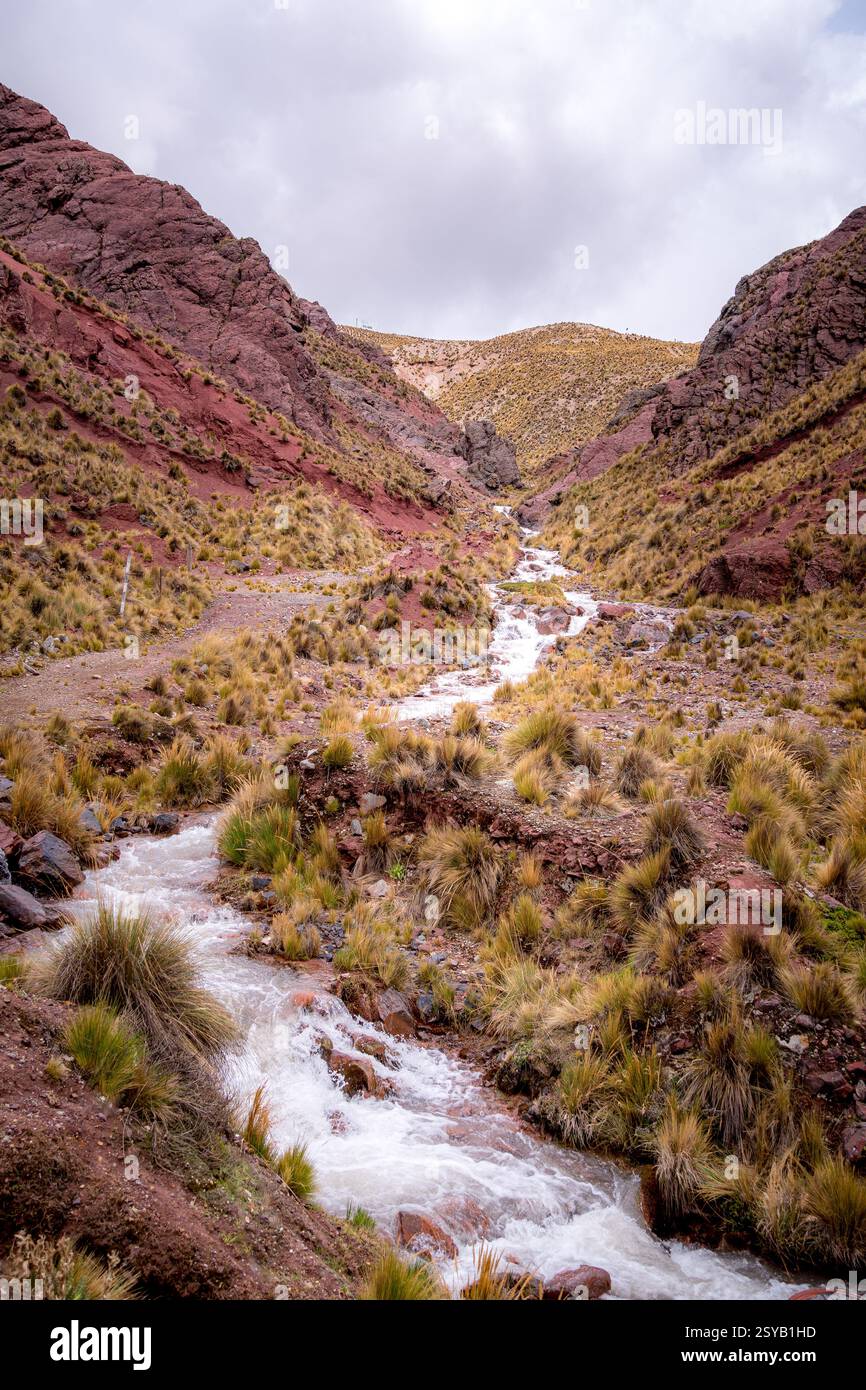 Scenic view of the Peruvian Andes with red soil, lush vegetation, and a ...
