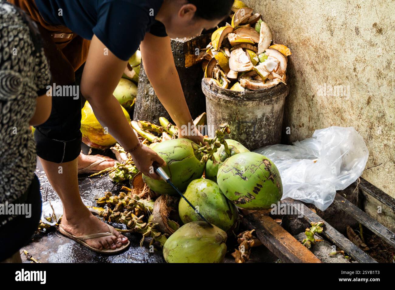 A person skillfully uses a knife to open coconuts, surrounded by ...