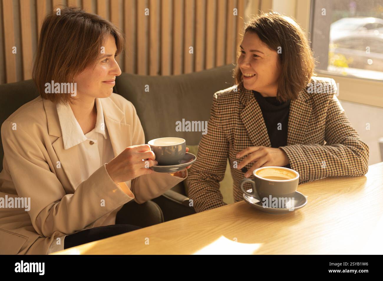 two women talk over coffee in a cafe and smilling Stock Photo - Alamy